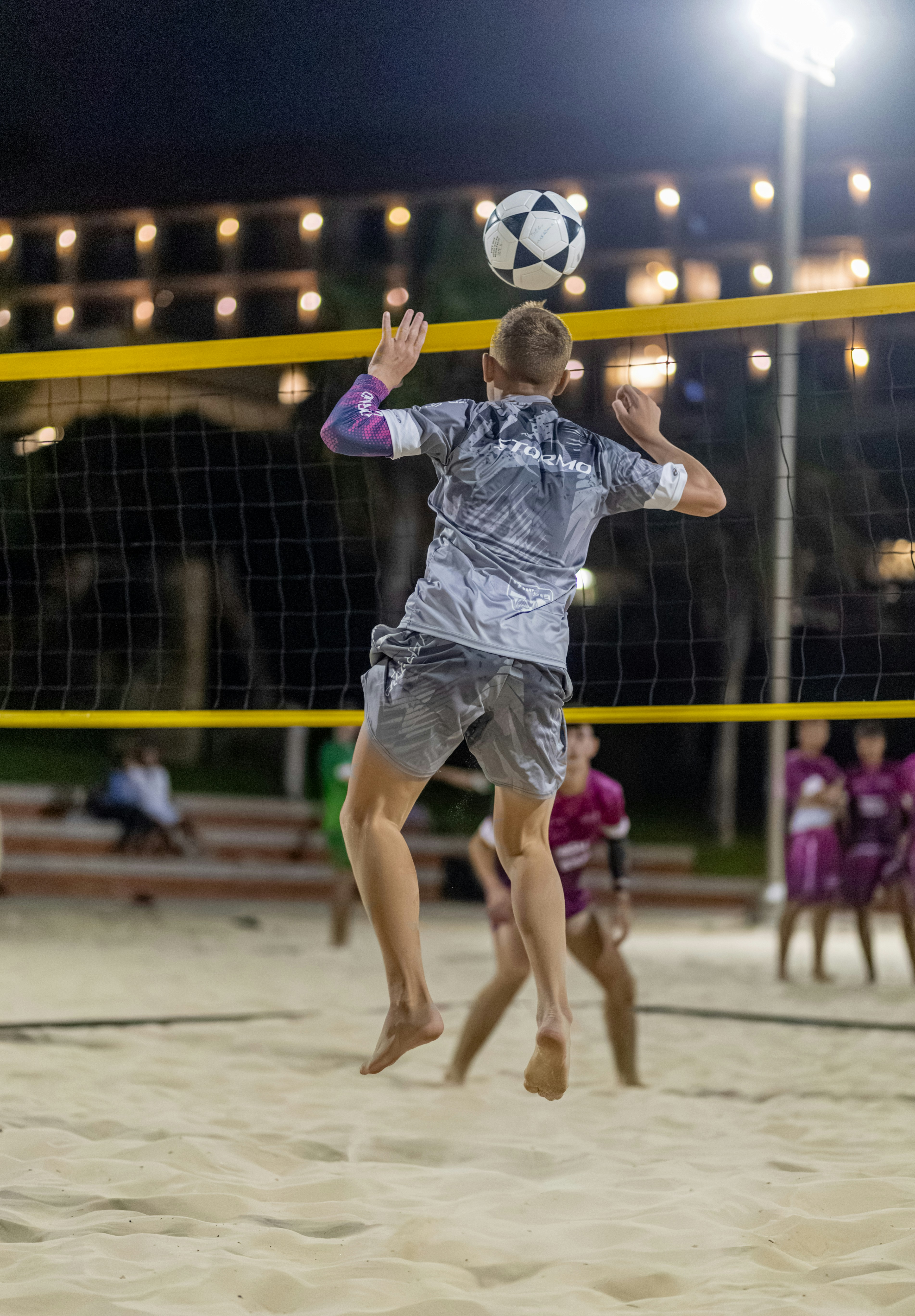 Mid-Air Volley: A Youth Sand Court Under Night Lights