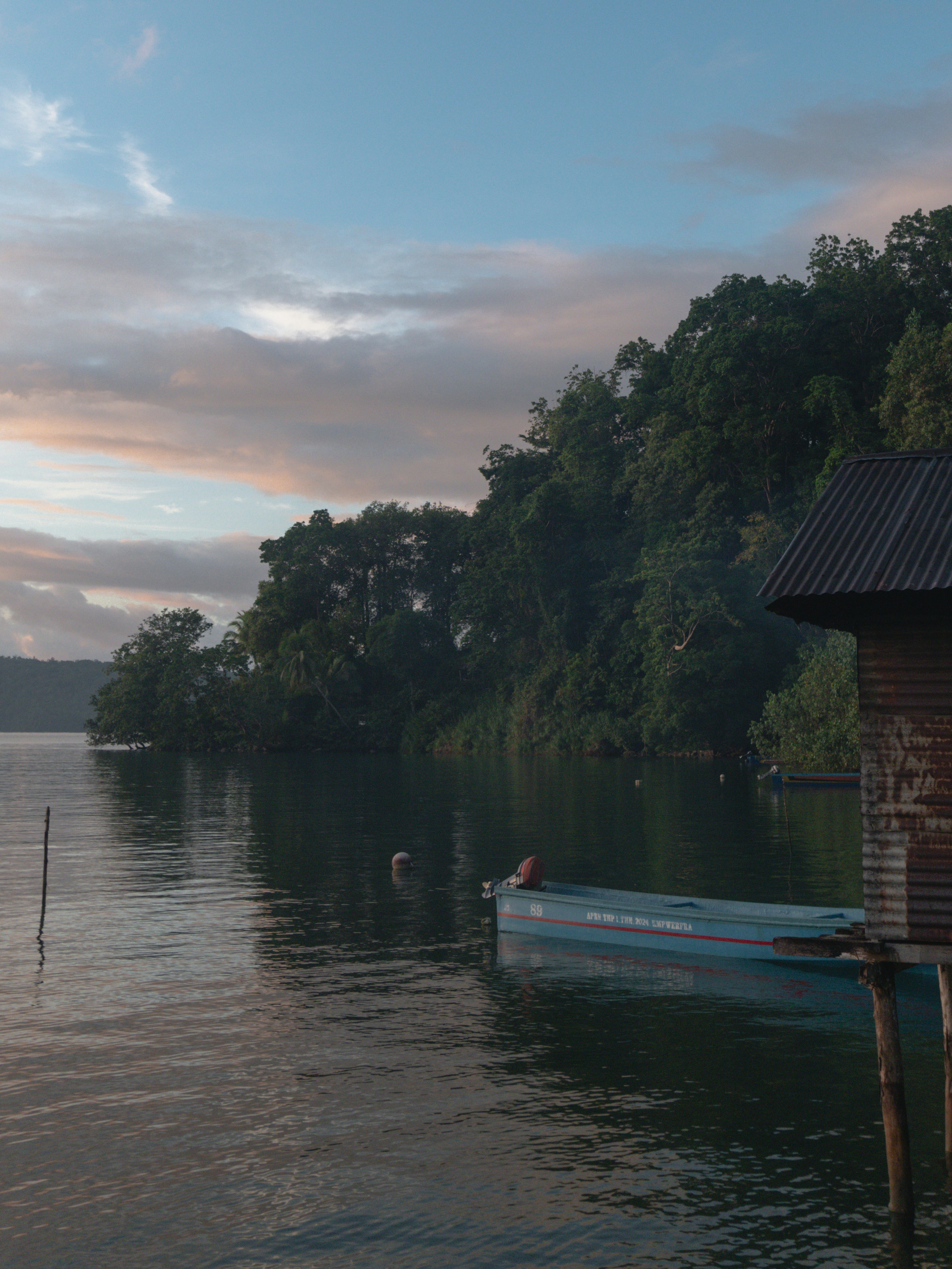 Dusk on Still Waters: A Quiet Boat Tied by a Wooden Hut