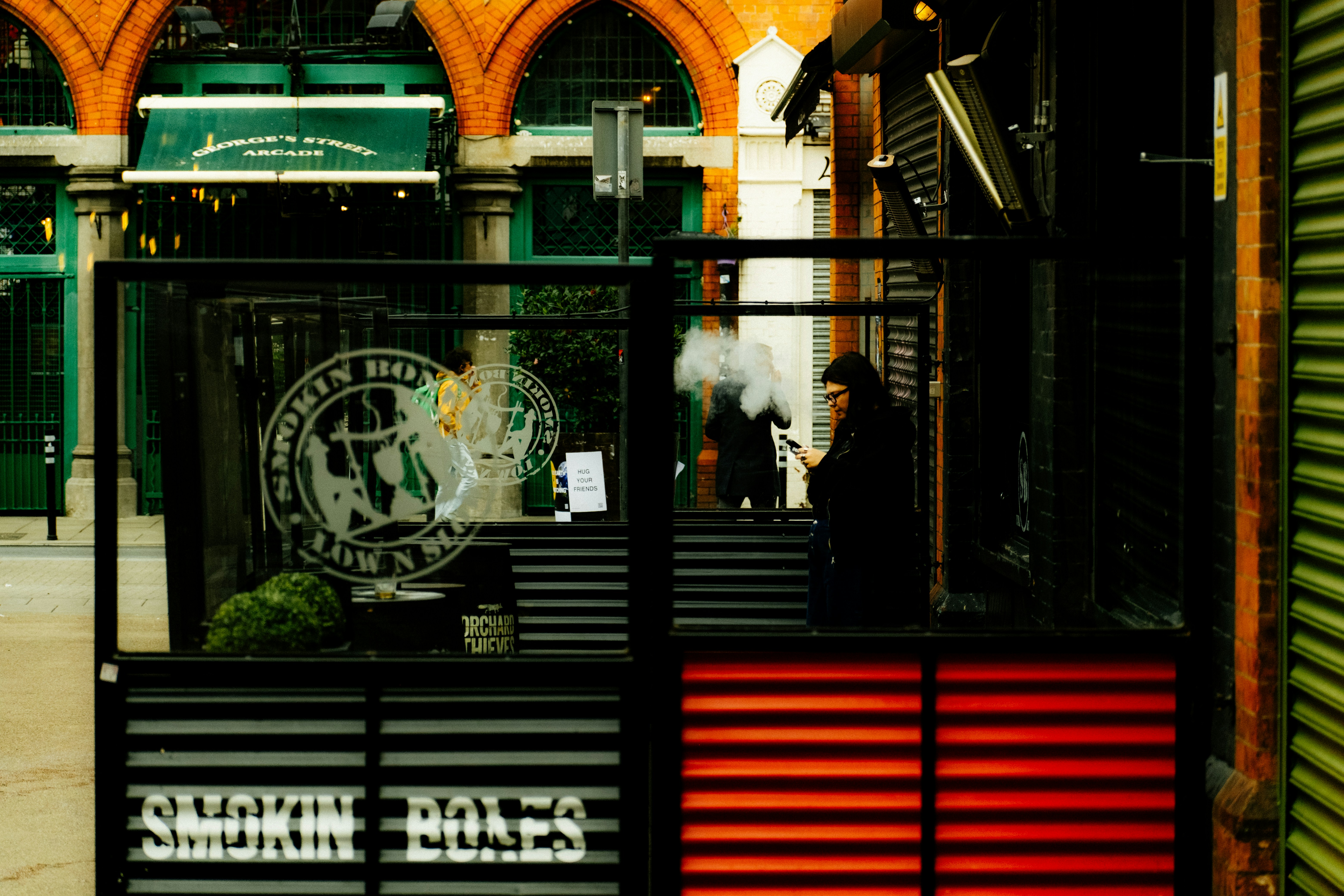 Lone figure behind glass in a brick-arched city arcade