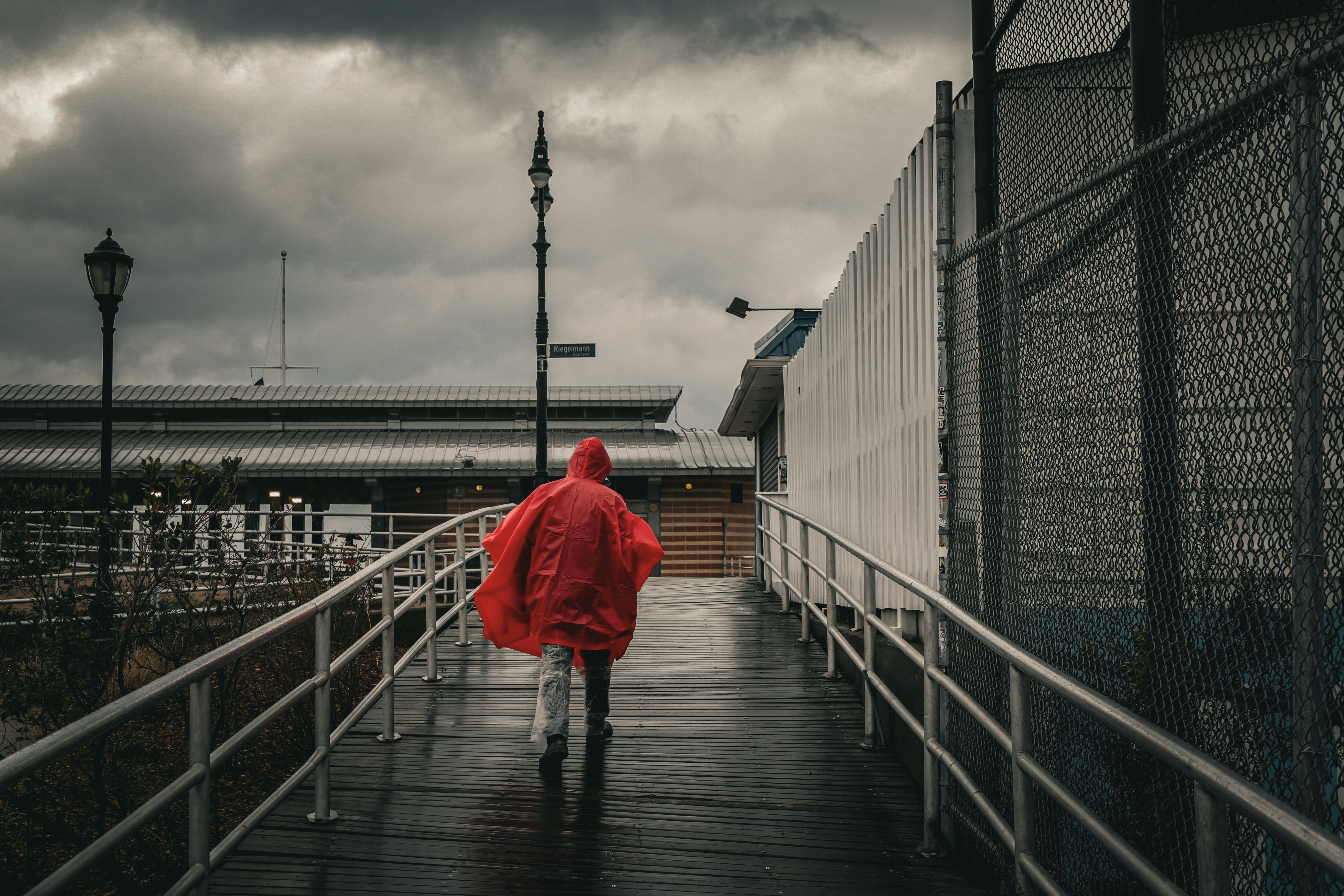Red Hooded Traveler Crossing a Rainy Pier