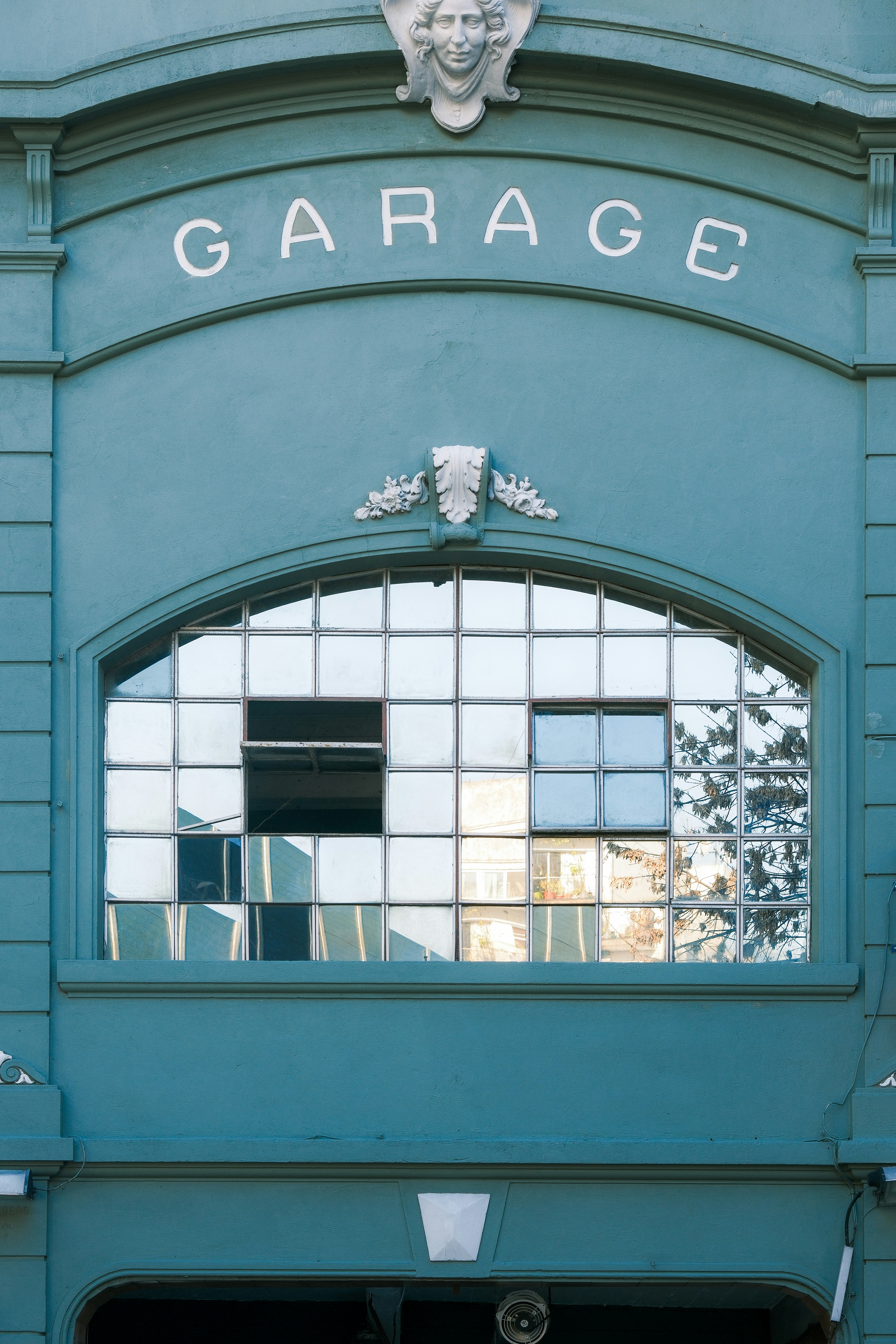 Teal Garage Facade: Reflections in an Arch Window Grid