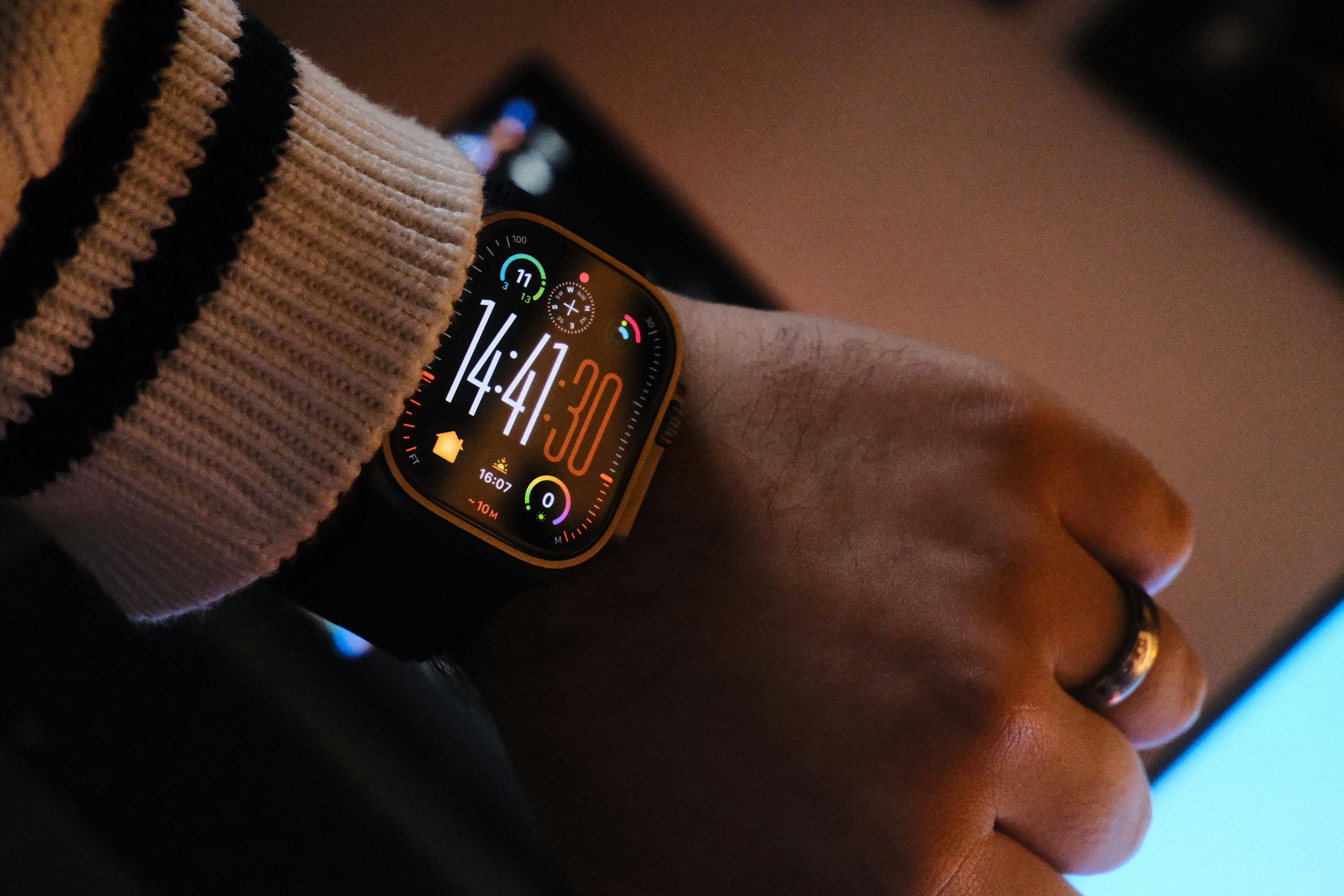 Colorful smartwatch glow peeks from a striped knit sleeve
