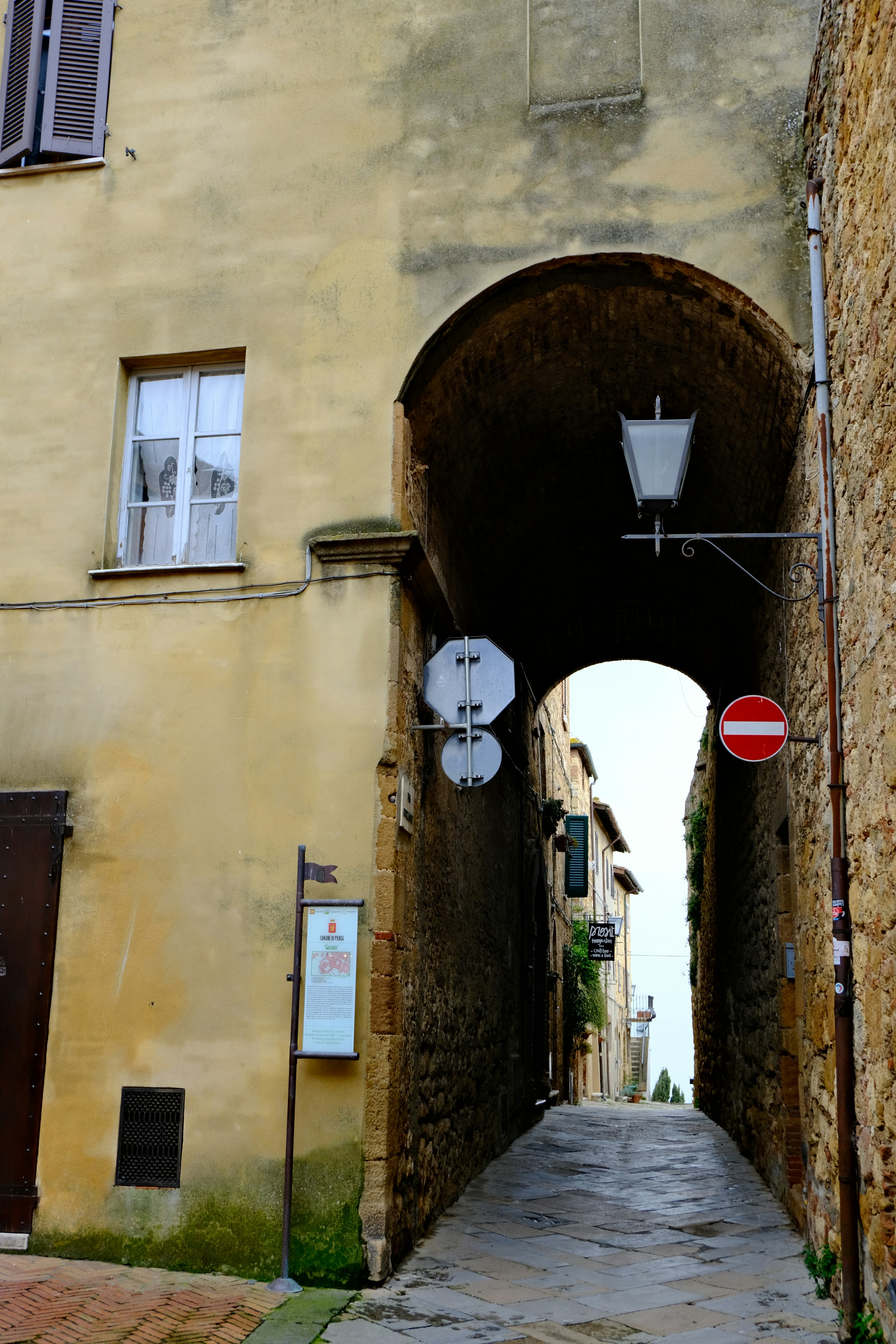 Archway Corridor: A Sunlit Alley Between Weathered Yellow Walls