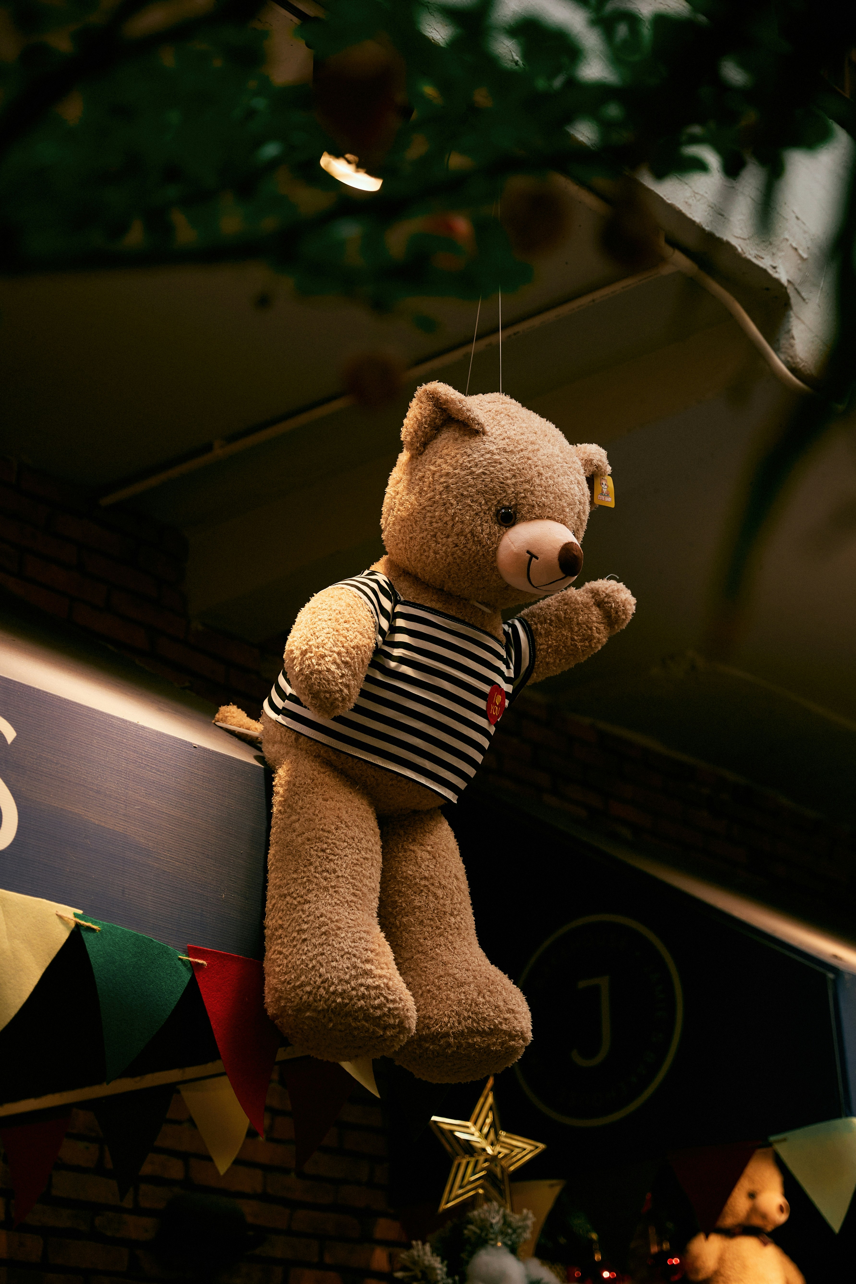Suspended Striped Teddy in a Warm-Glow Shop Amid Festive Bunting