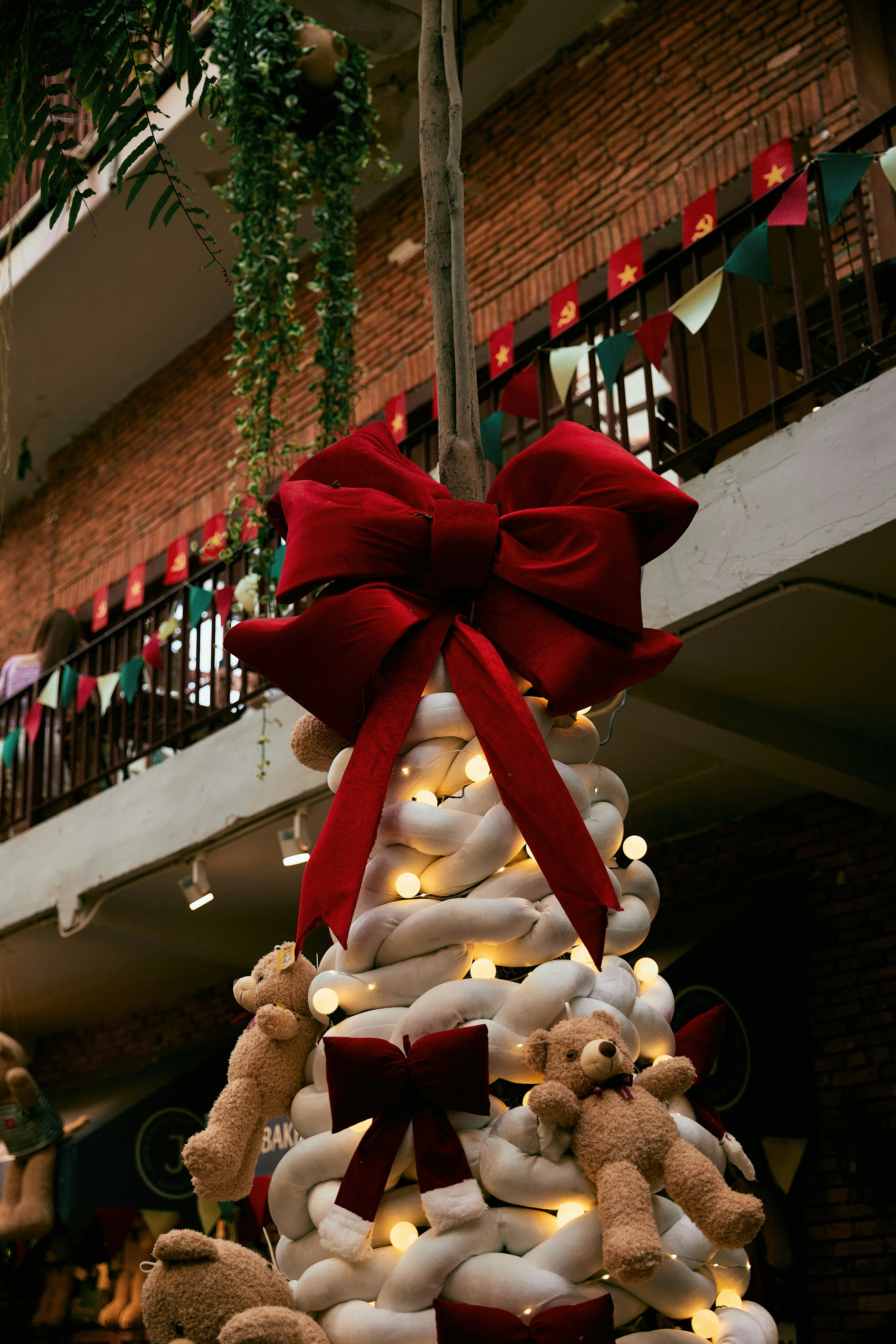 Giant plush holiday tree crowned with a velvet bow in a brick-wrowled atrium