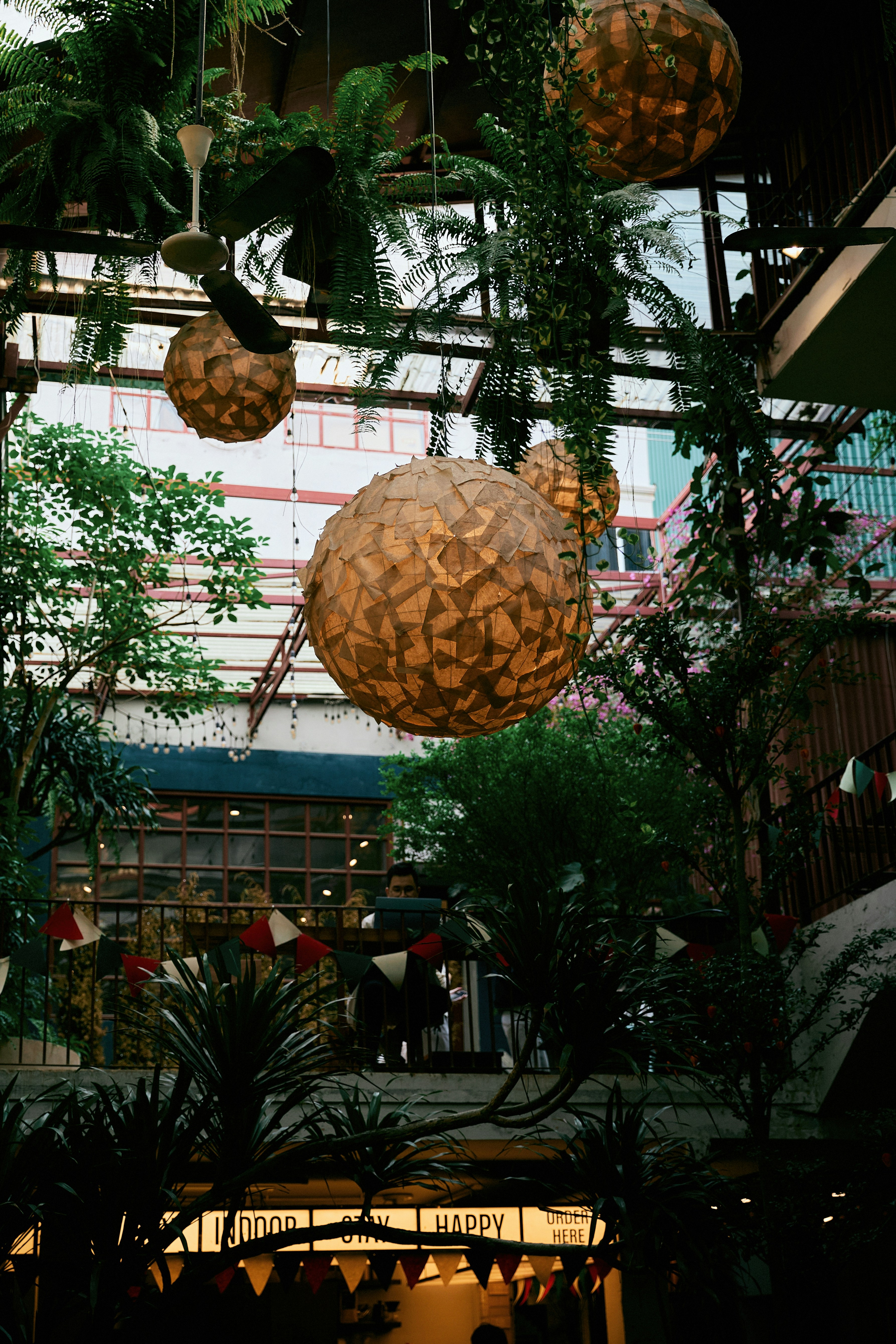Geometric Lantern Orbs Hover Over a Lush Indoor Atrium
