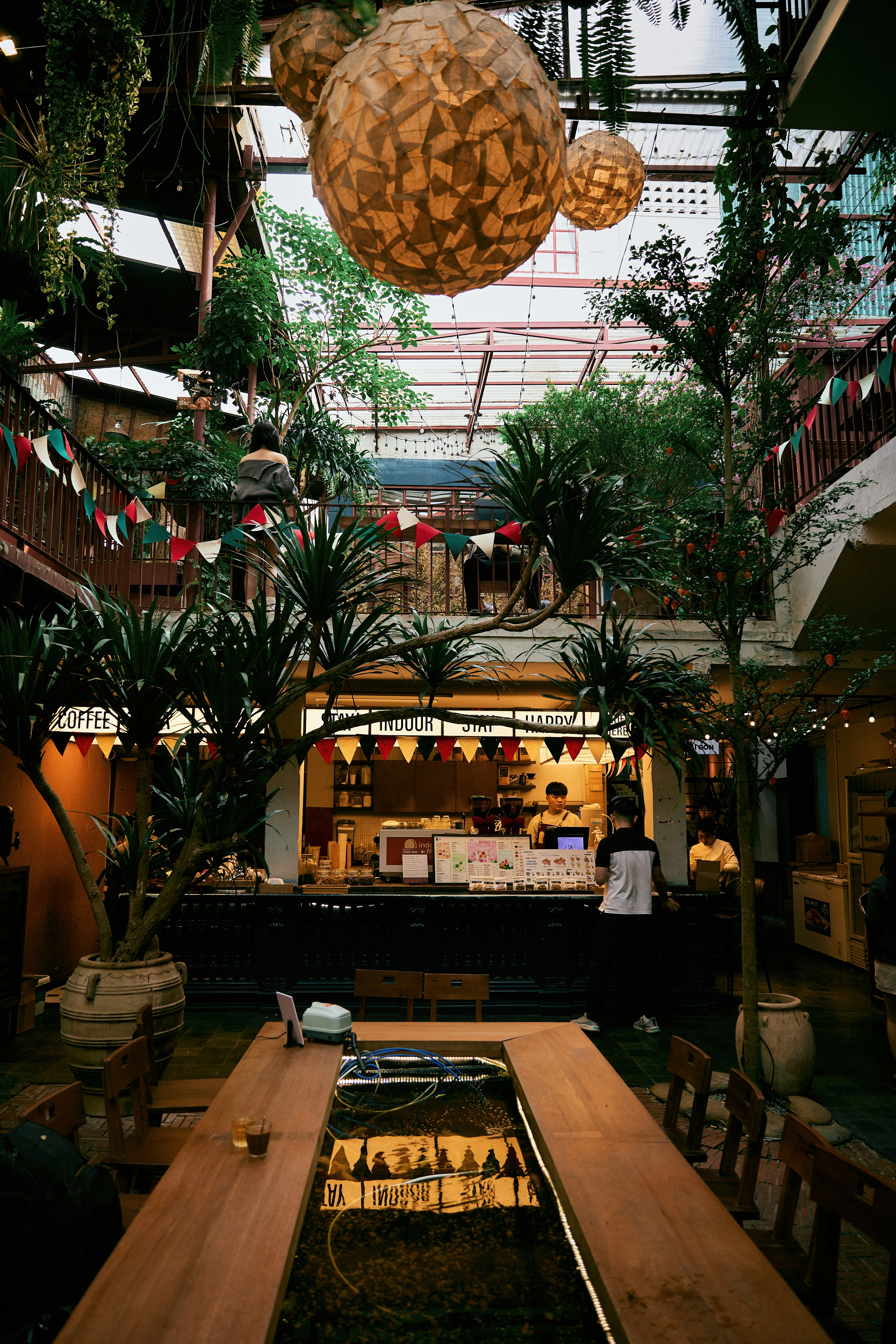 Geometric Lanterns Hover Over a Lush Indoor Courtyard Café