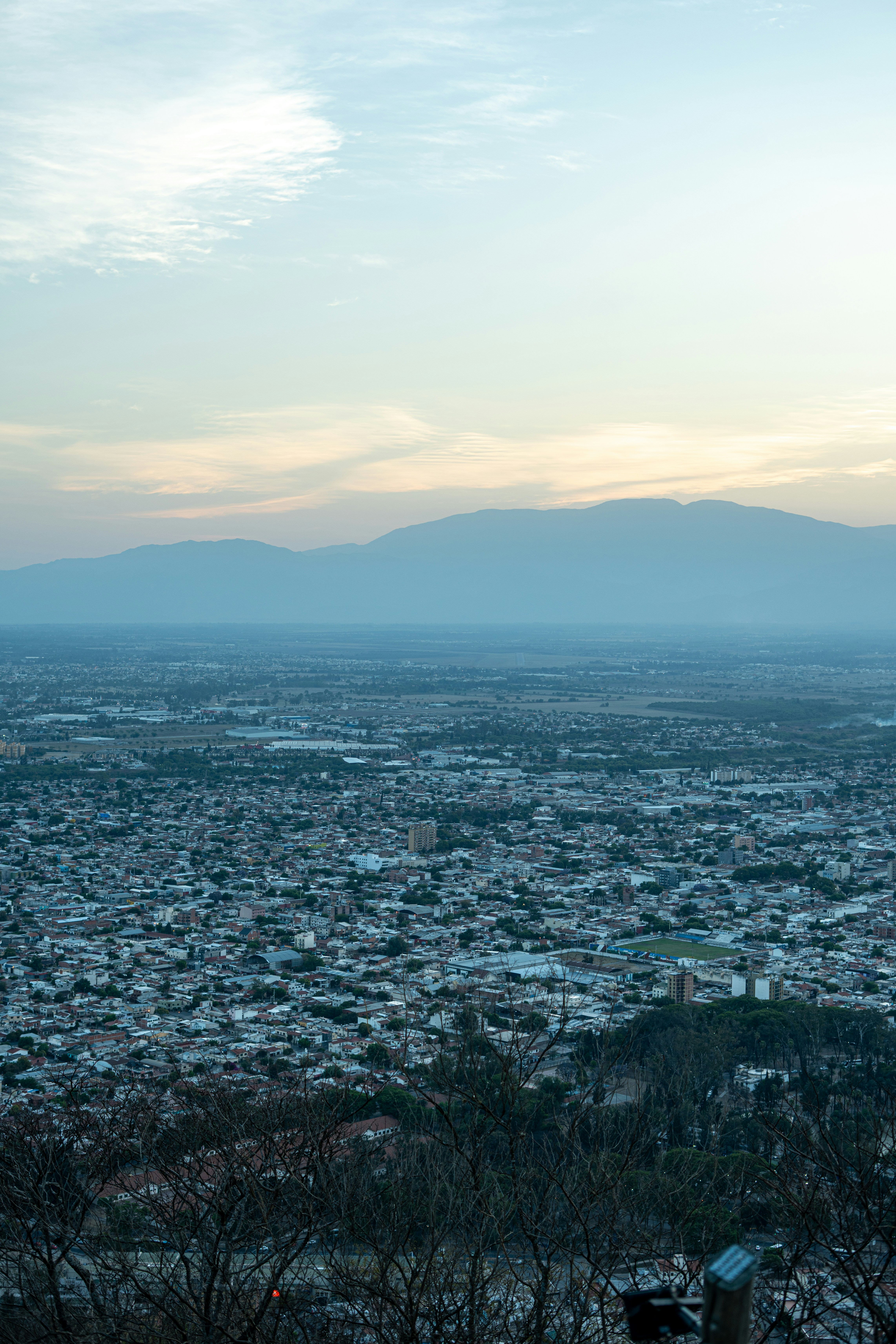 Soft evening light paints the mountains around Salta in warm tones as the sun sets behind the horizon, creating a serene panoramic landscape.