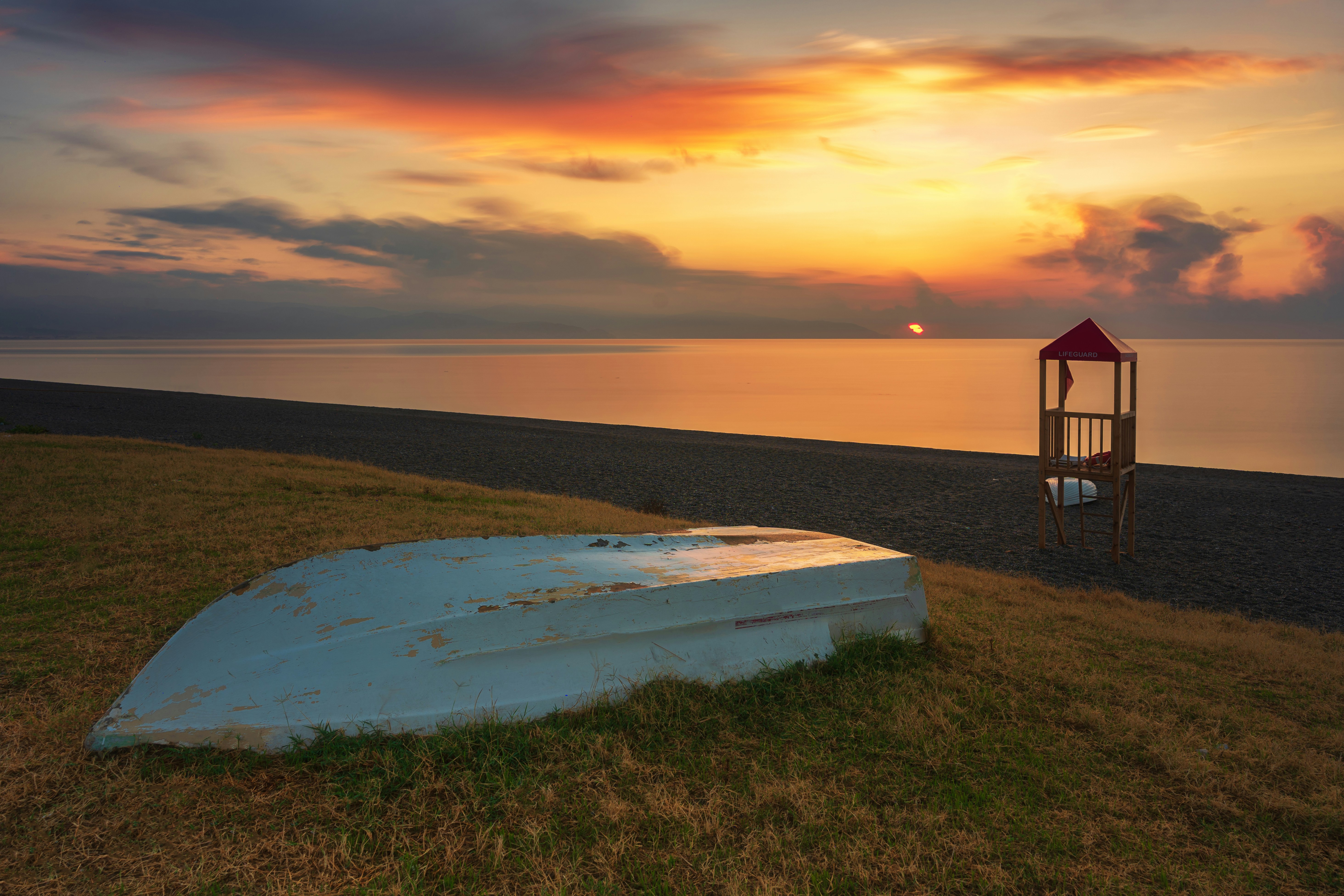 Dusk by the Shore: A Quiet Boat and Lifeguard Tower on Calm Sands