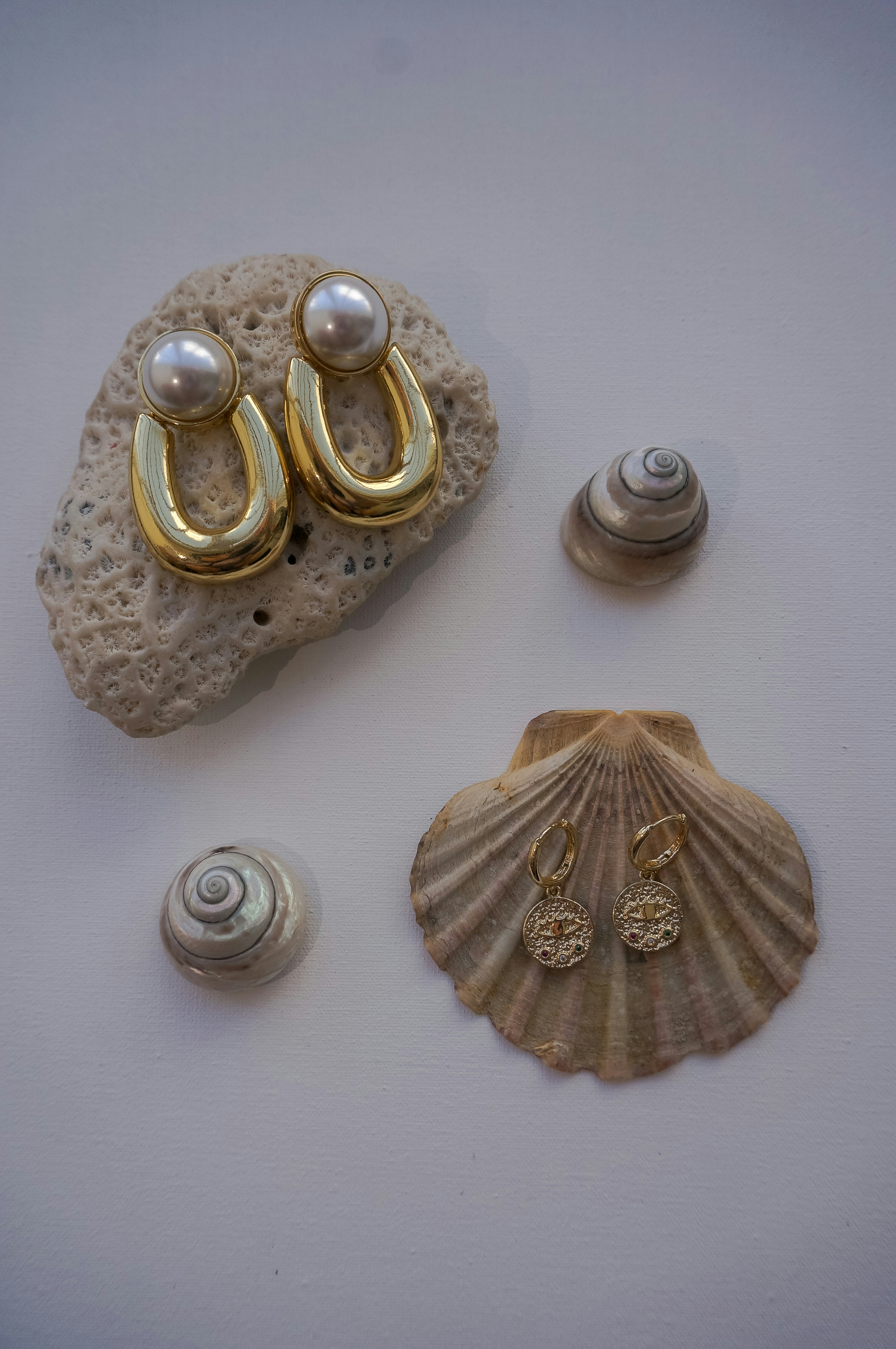 Gold Crest Earrings Resting on a Textured Sea Stone