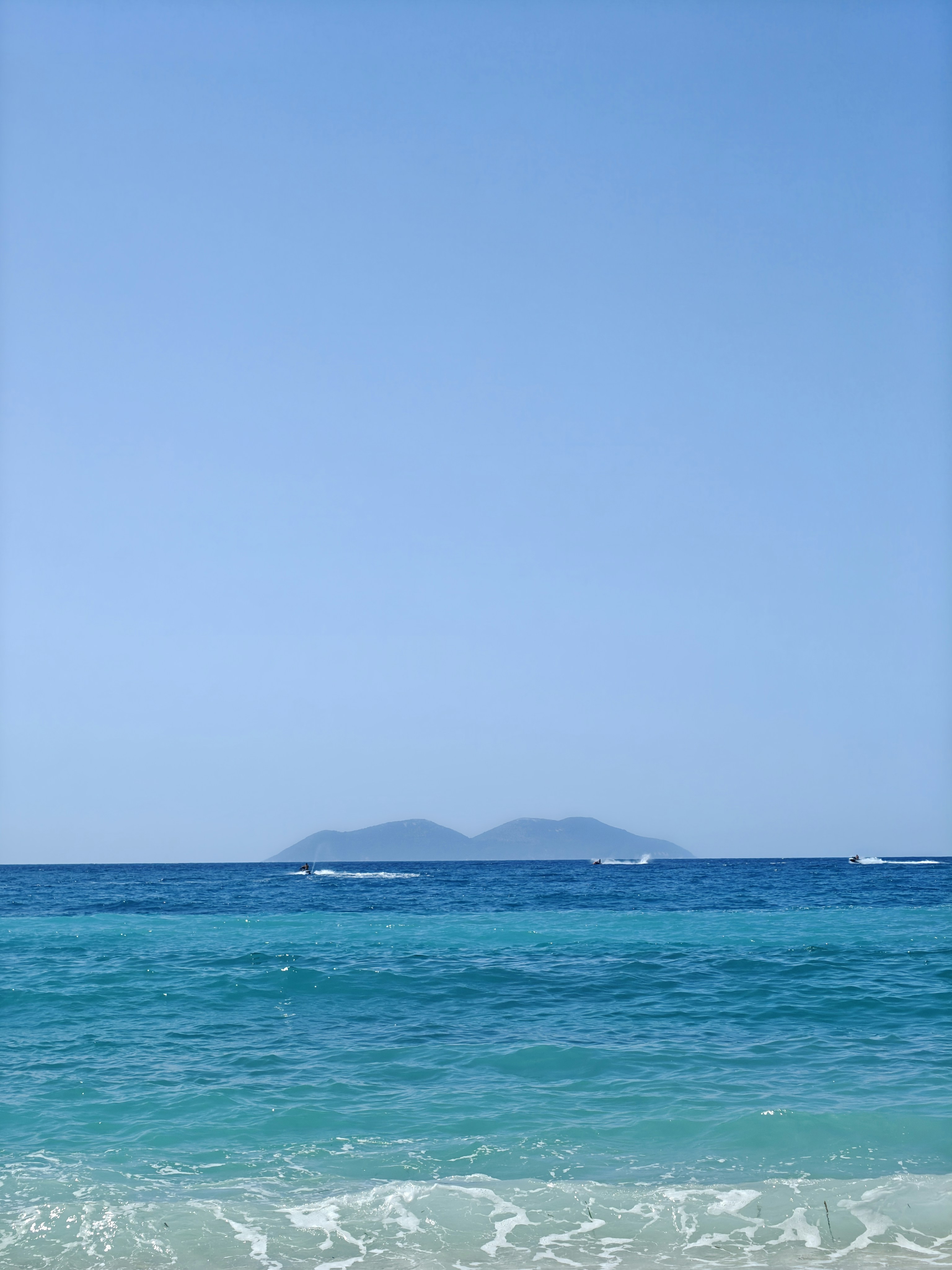 Clear blue sky over turquoise ocean with distant islands