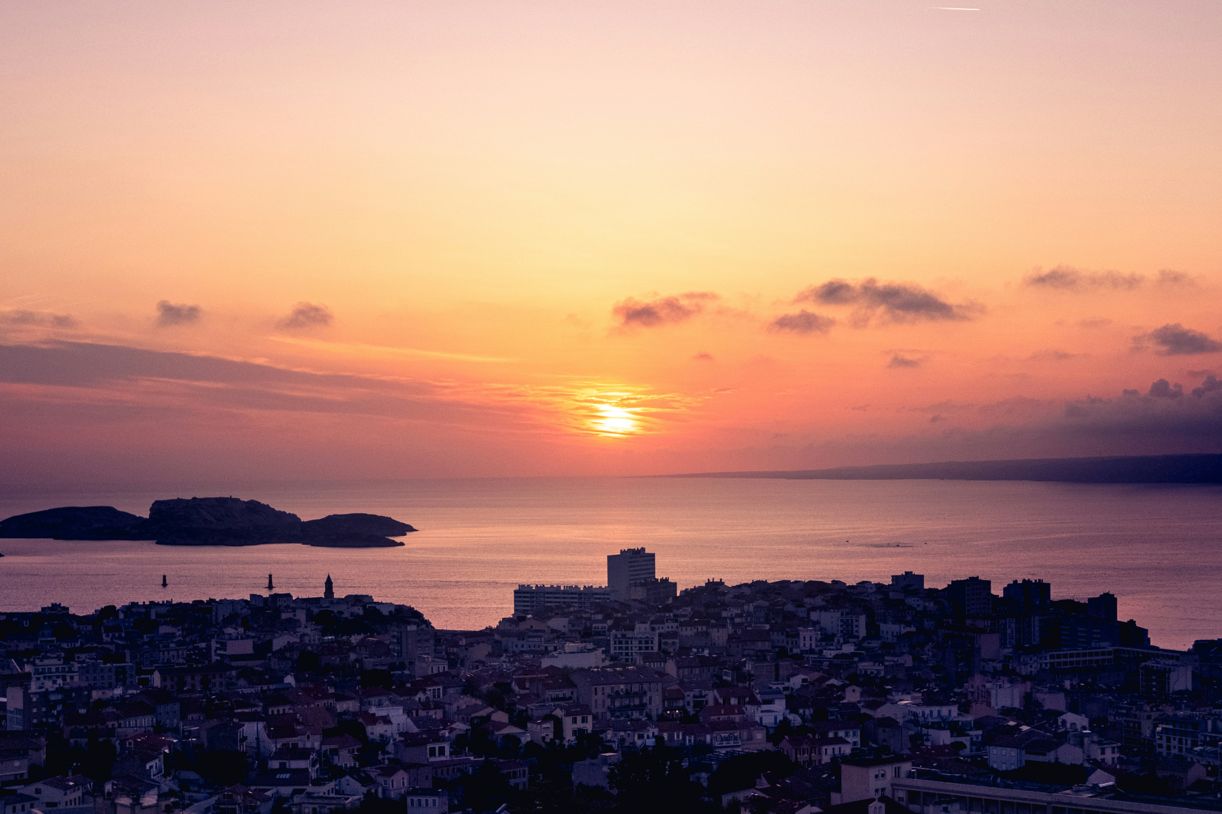 Crimson Horizon Over a Silhouetted Coastal City at Dusk