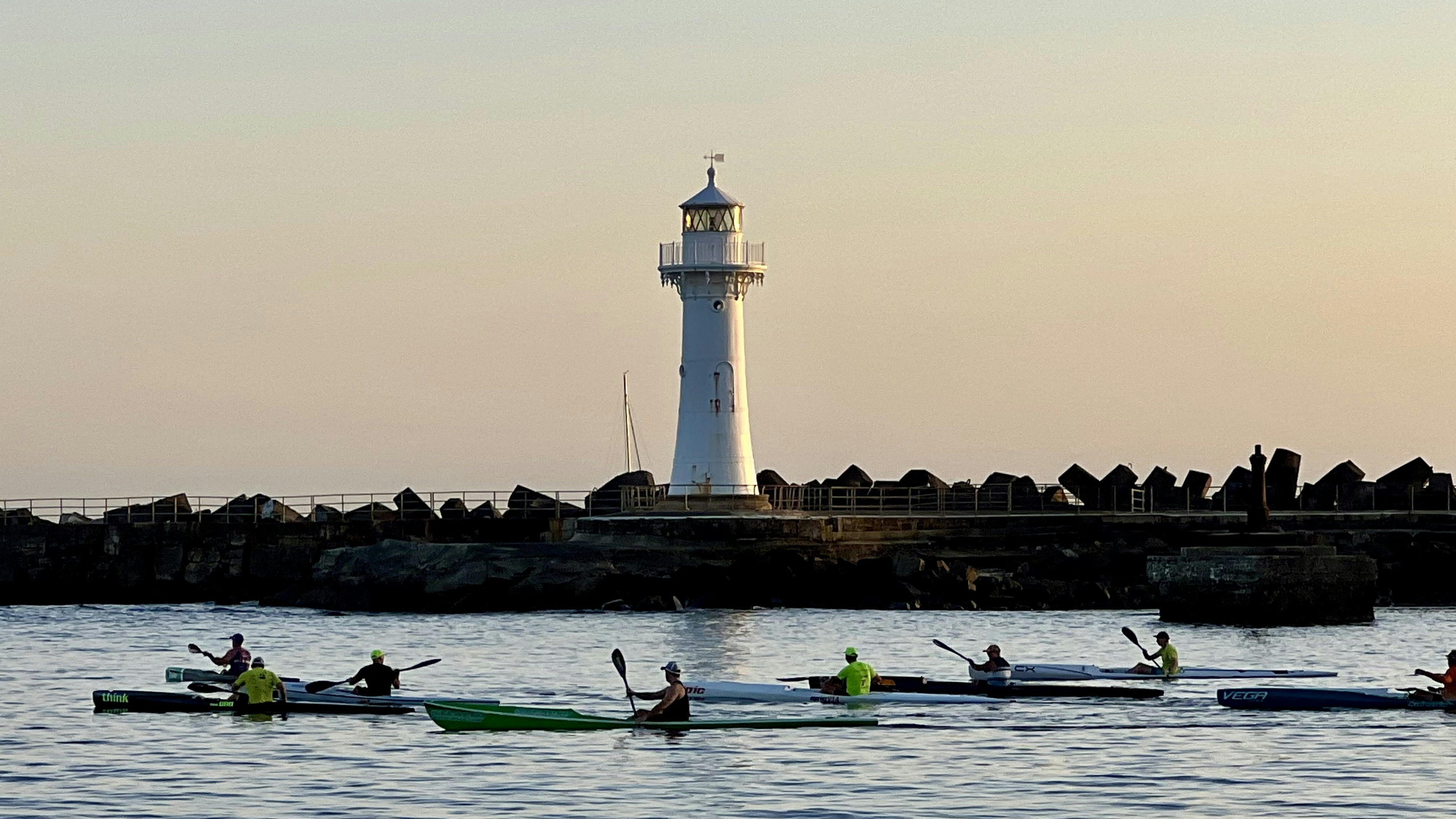 Beacon at the Breakwater: Rowers Under a Golden Coastal Sky