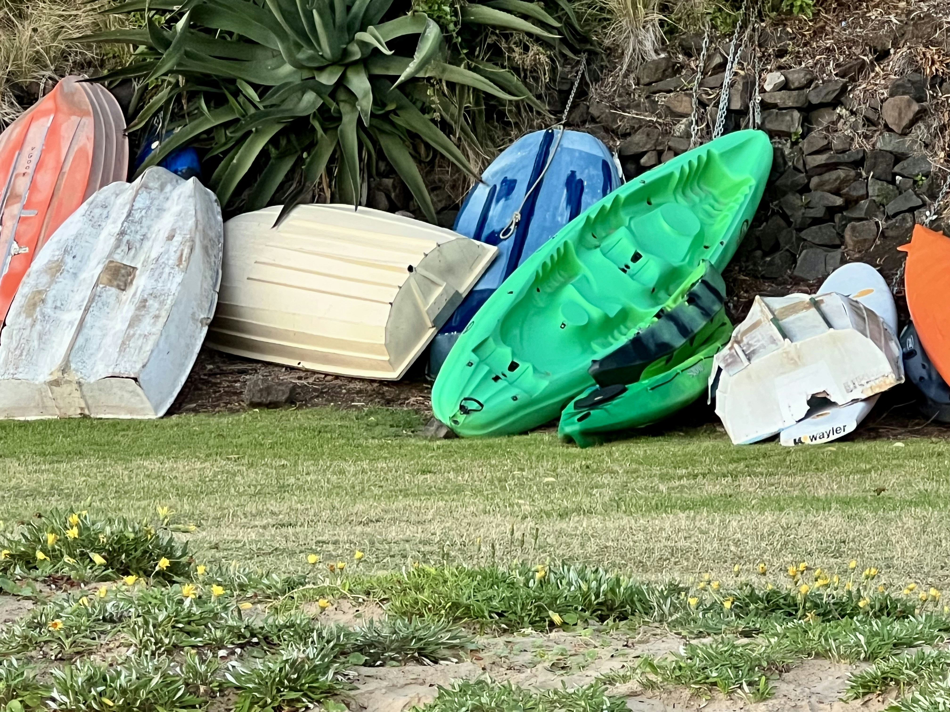 Green Kayak as Centerpiece Among Overturned Colorful Boats