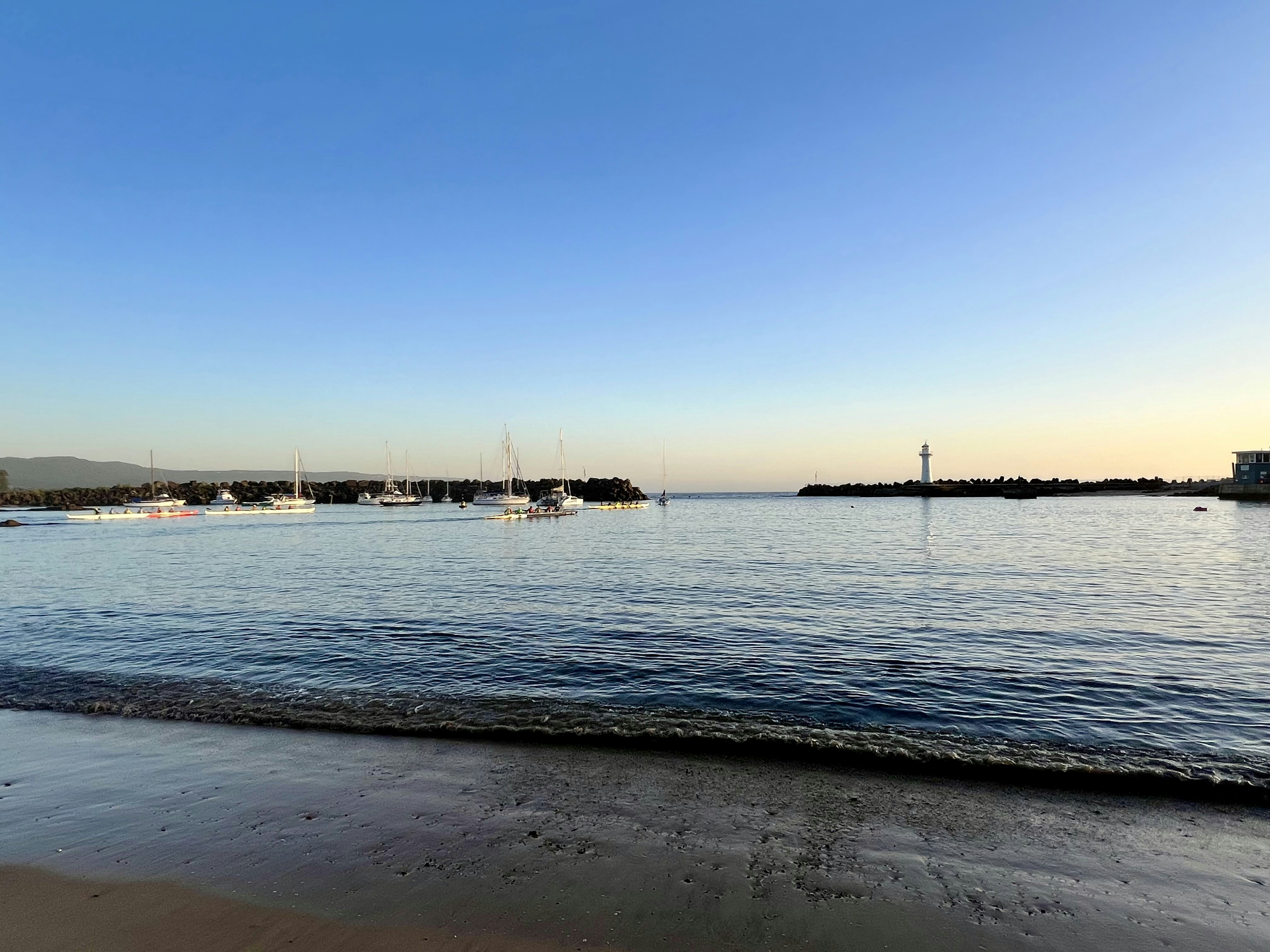 Dusk at the Harbor: Boats Rest by the Breakwater Beneath a Quiet Lighthouse