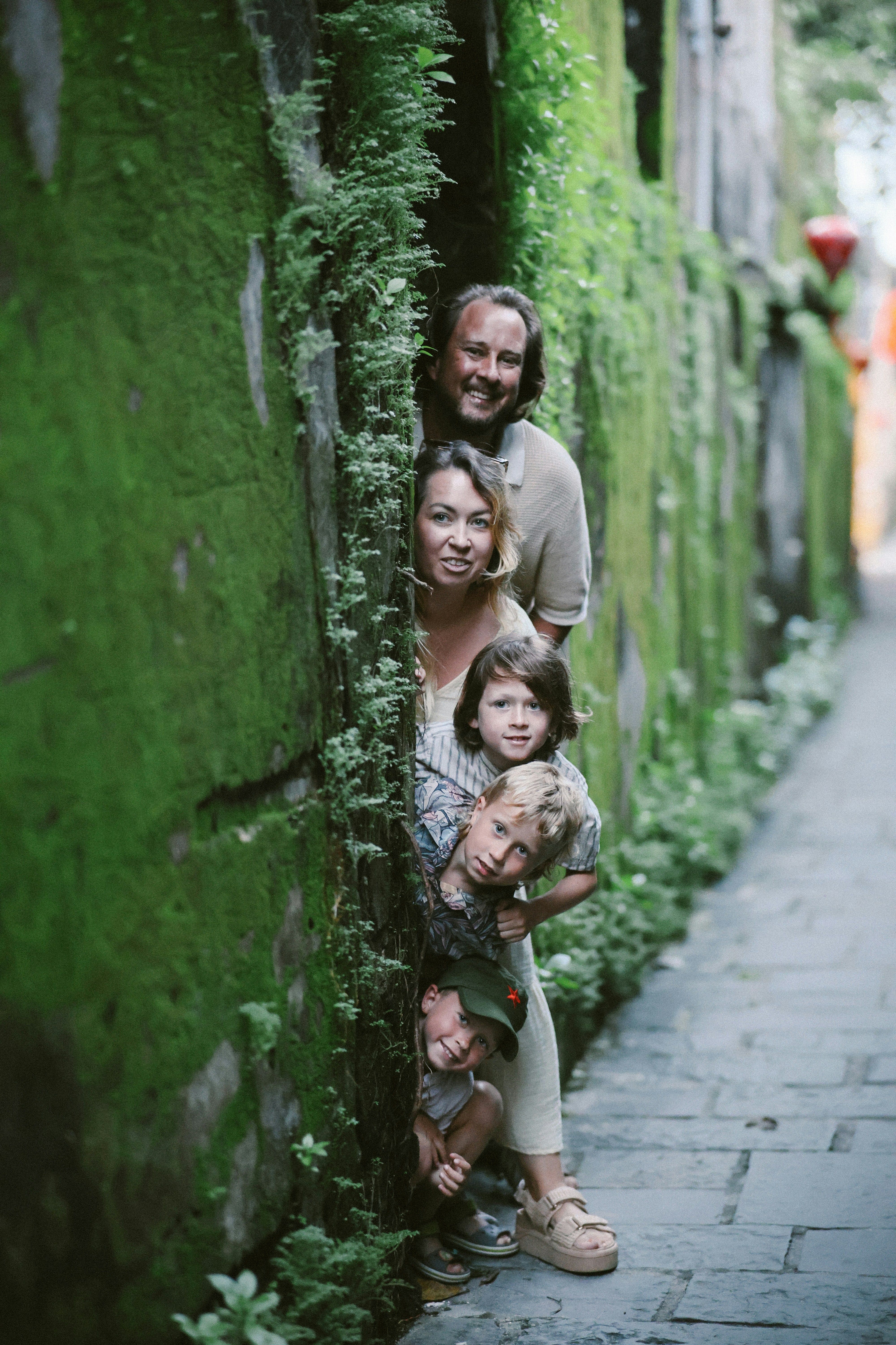 Green Corridor Family Peek: A Cascade of Smiles Between Mossy Walls