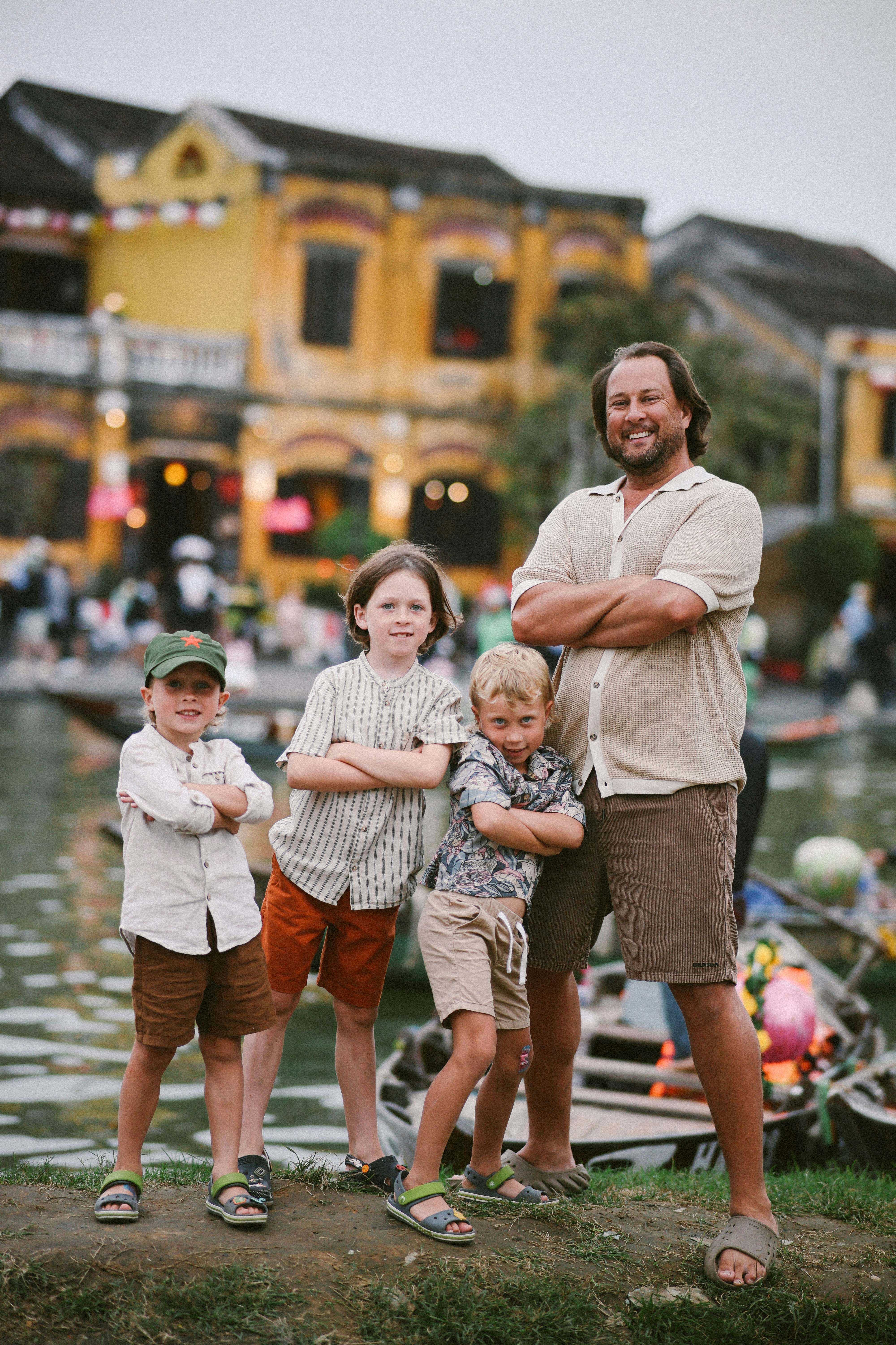 Father and three sons pose in front of yellow buildings. photo – Free ...