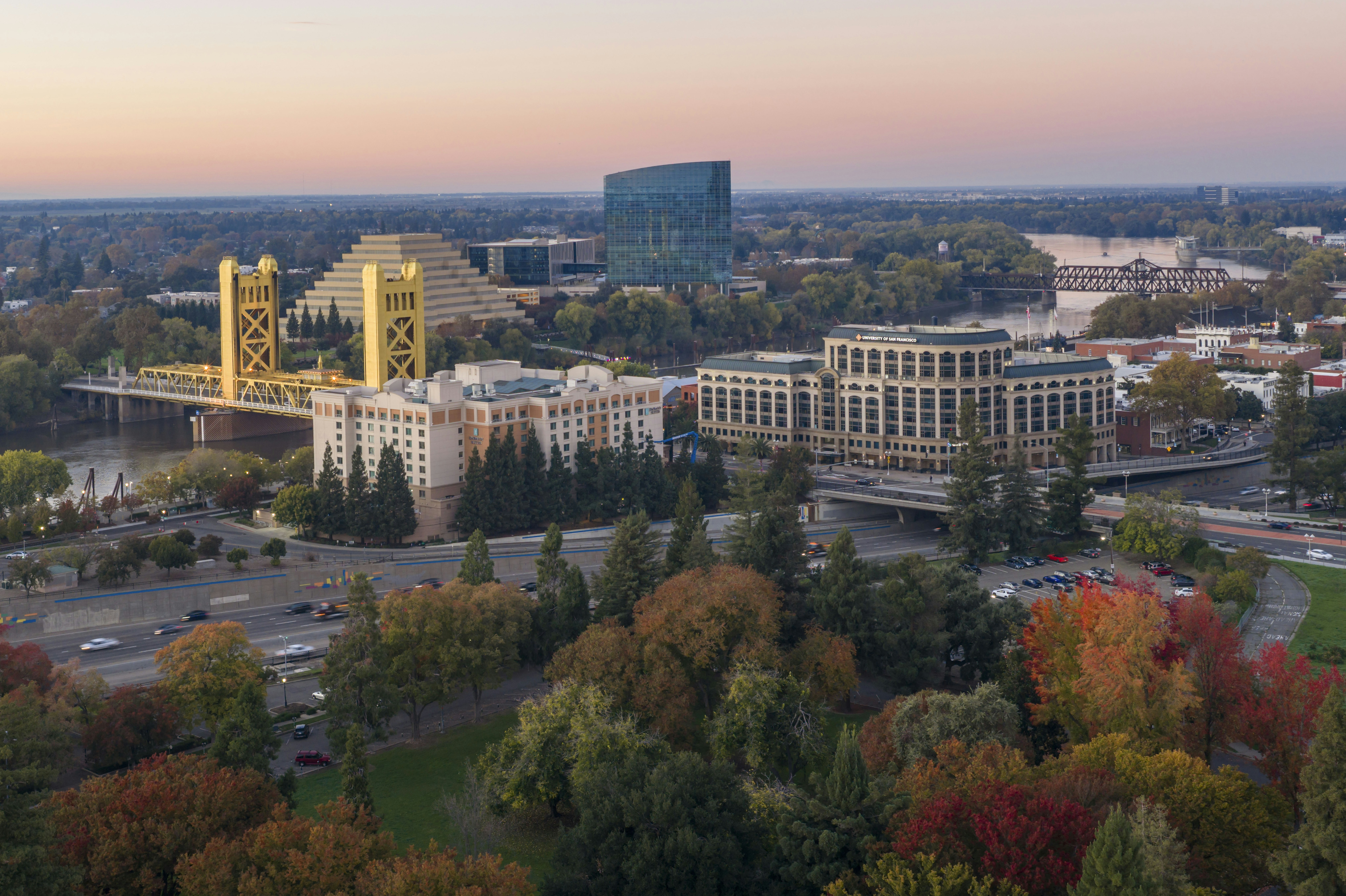 Twin-Towered Golden Bridge Framing a Riverside City at Dusk