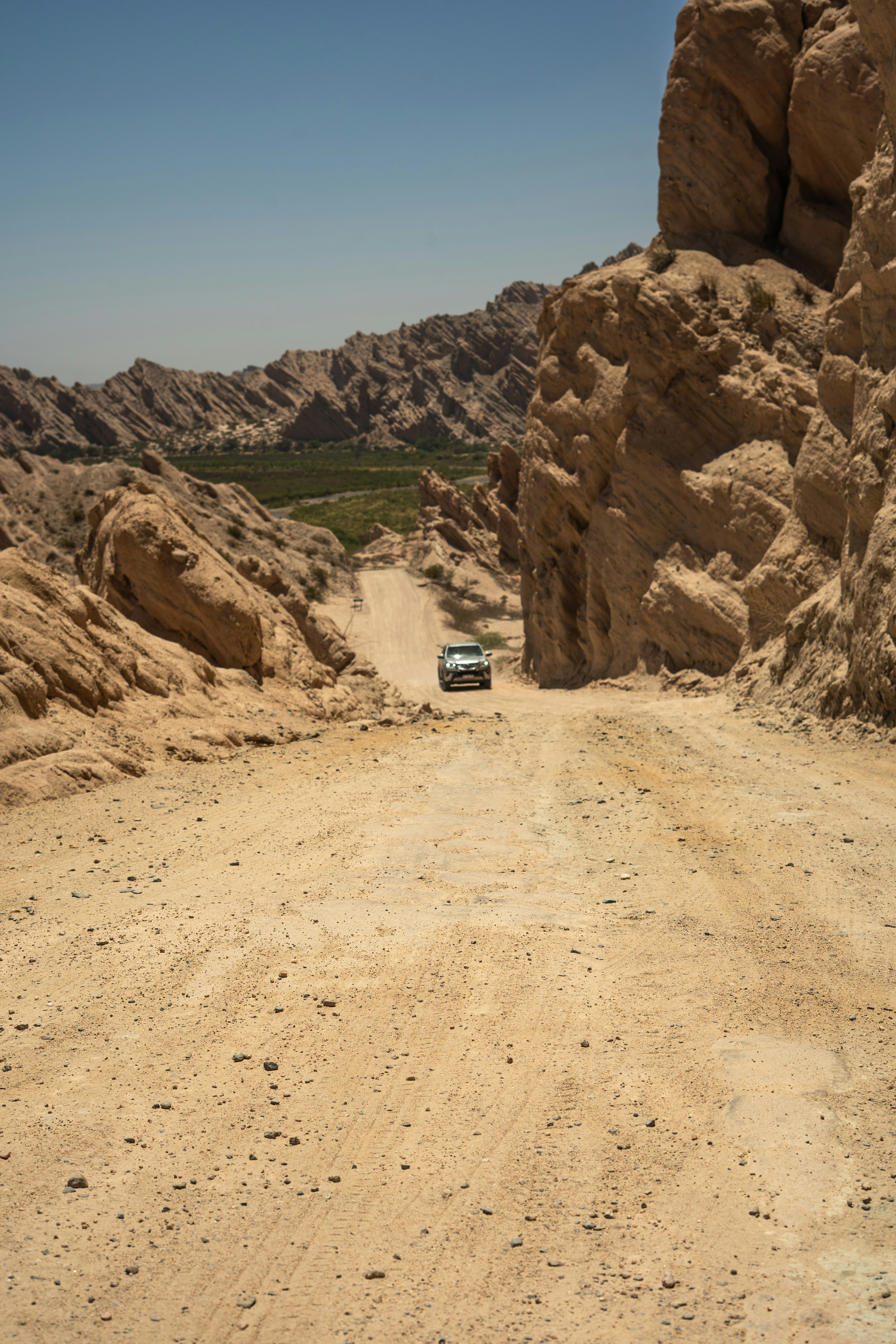 Dust Road to the Oasis: Car Against a Canyon Backdrop