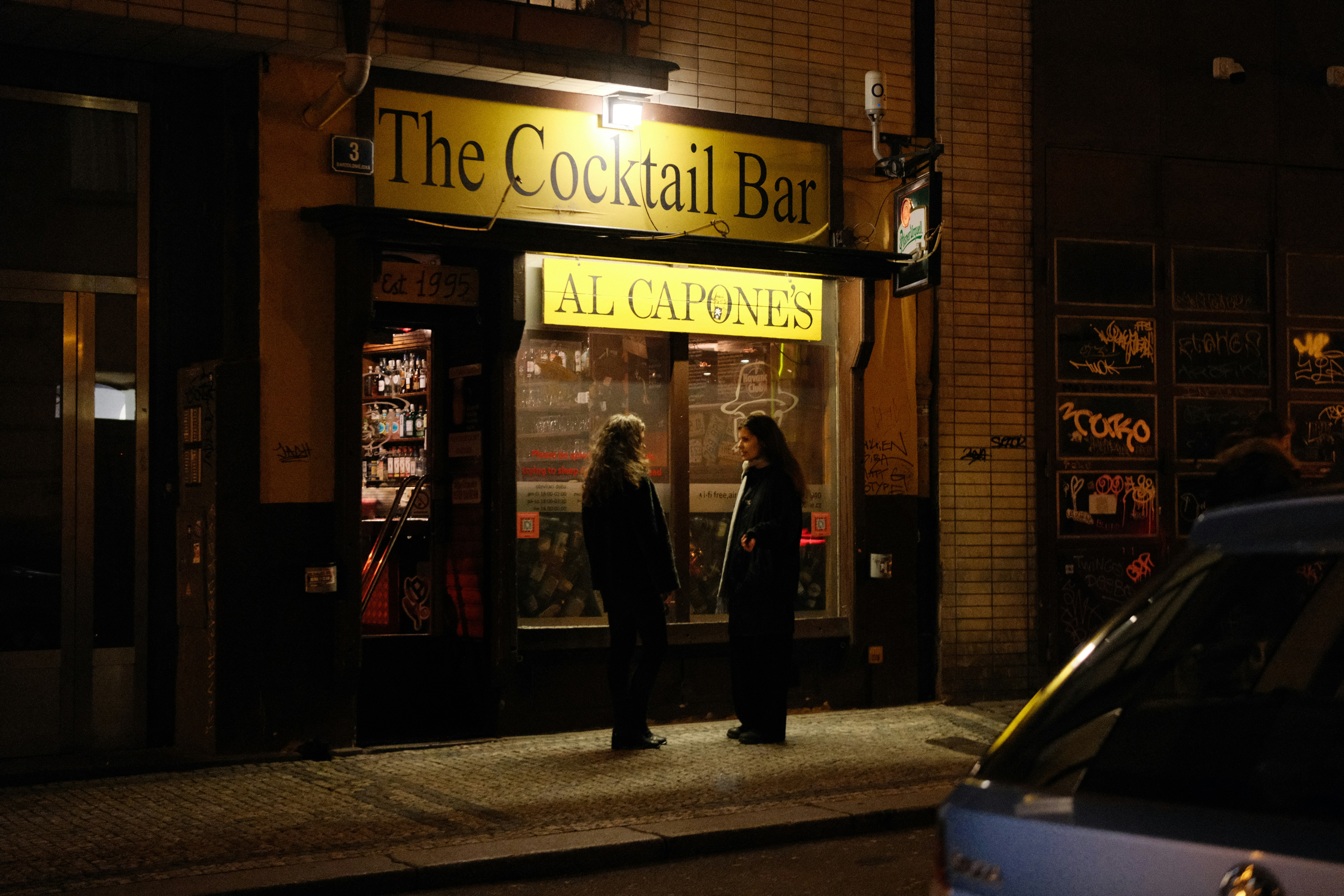 People chatting outside a cocktail bar at night