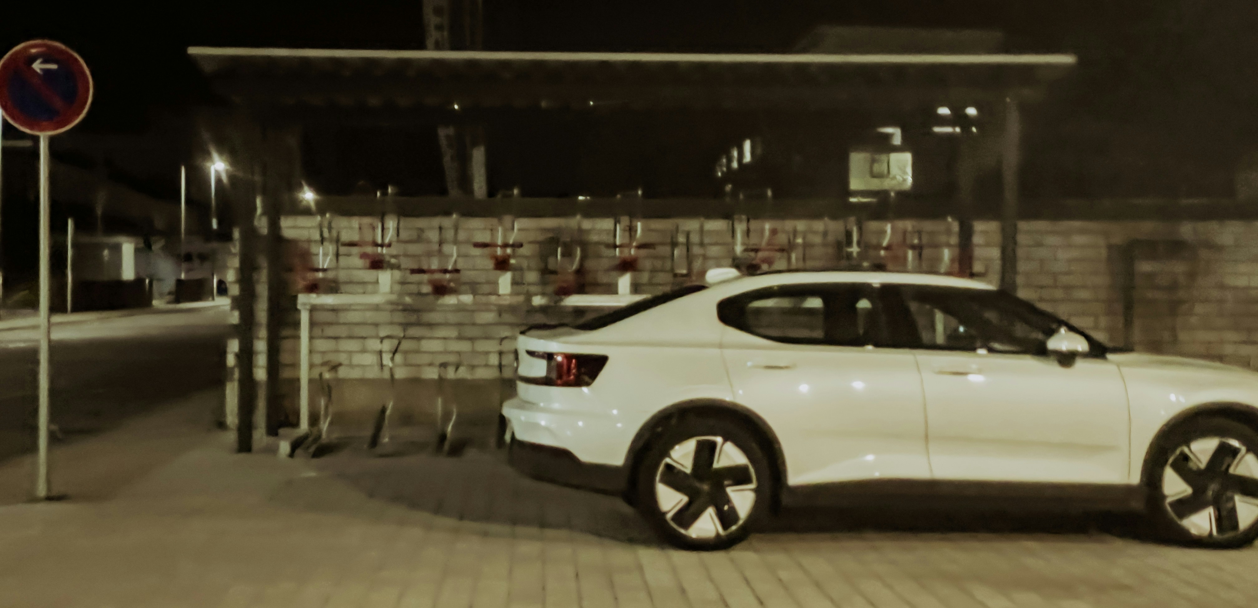 Nighttime street snapshot: white SUV parked under a shelter