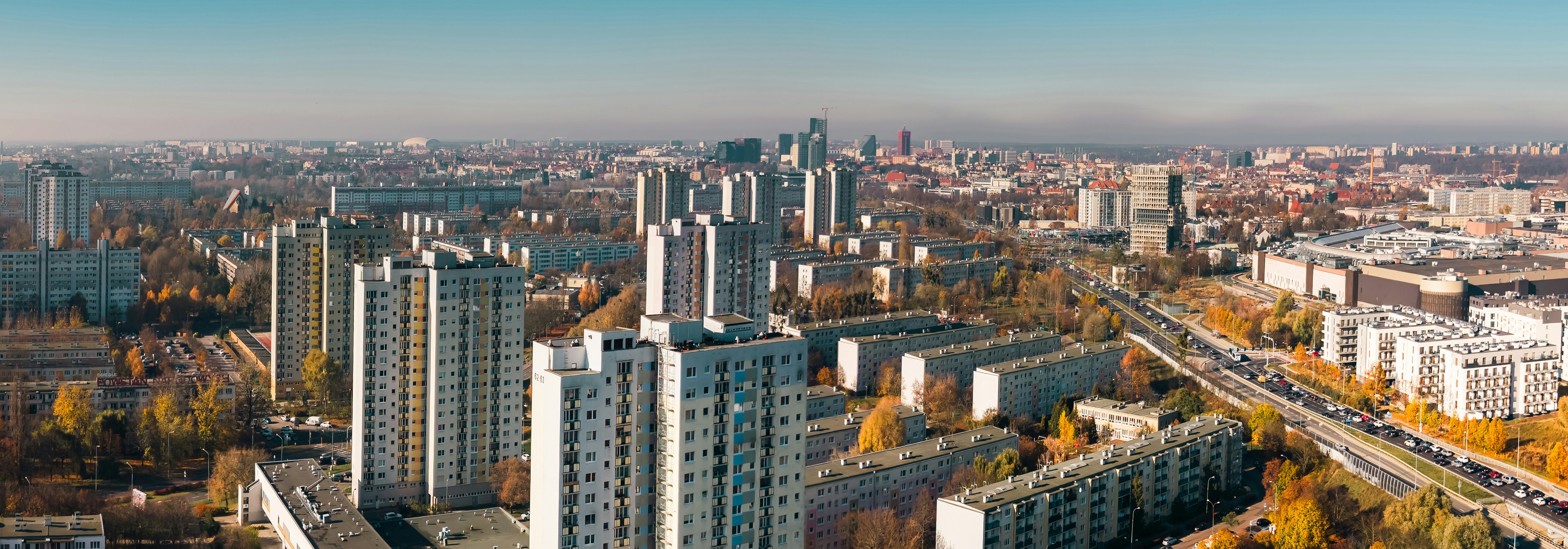 City Skyline Residential District Autumn Day. Panoramic aerial view of a densely populated urban area with residential blocks, modern skyscrapers, and colorful autumn trees under a clear sky