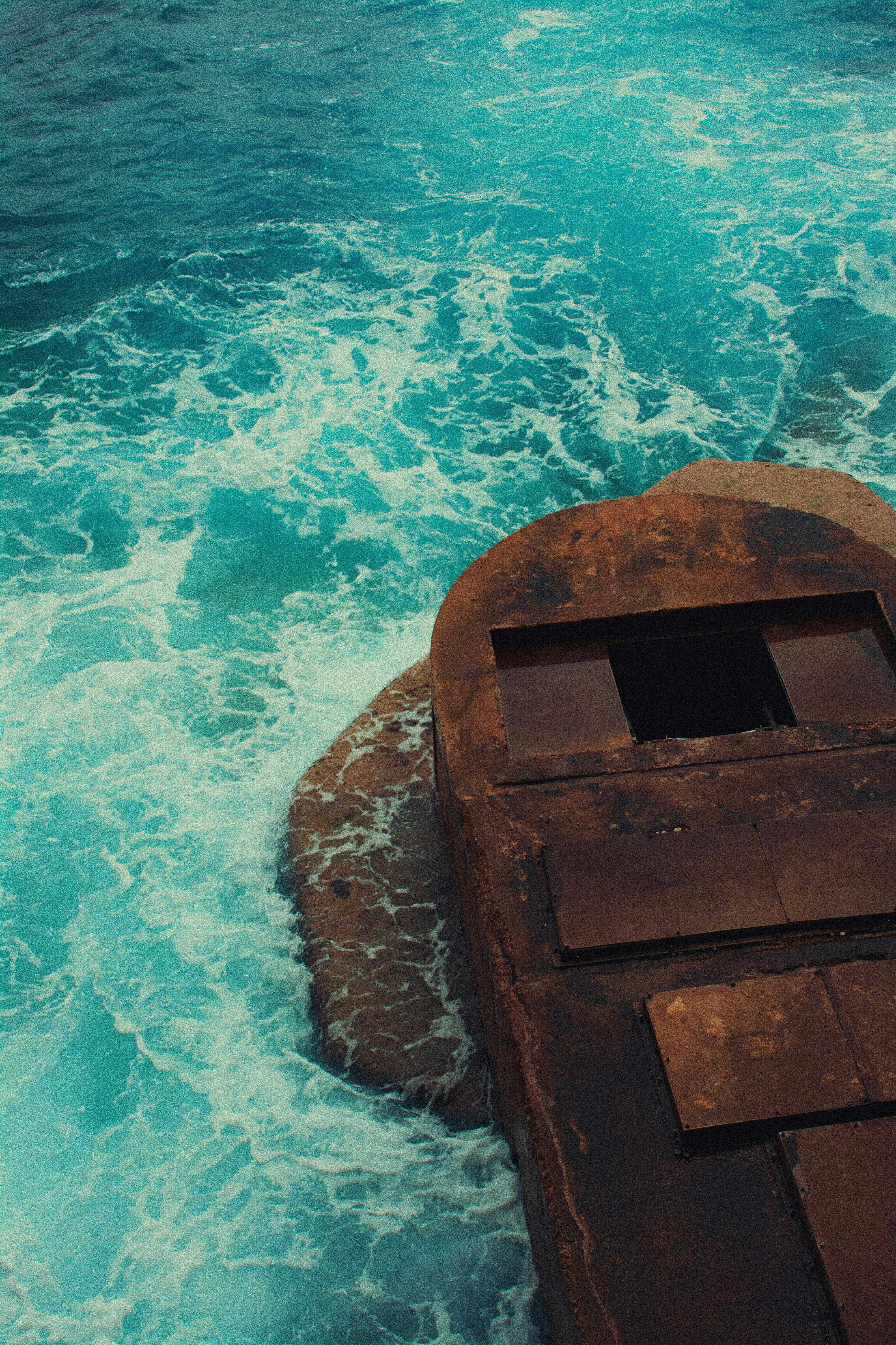 Rust and Tide: A Weathered Hatch Meets Turquoise Seas