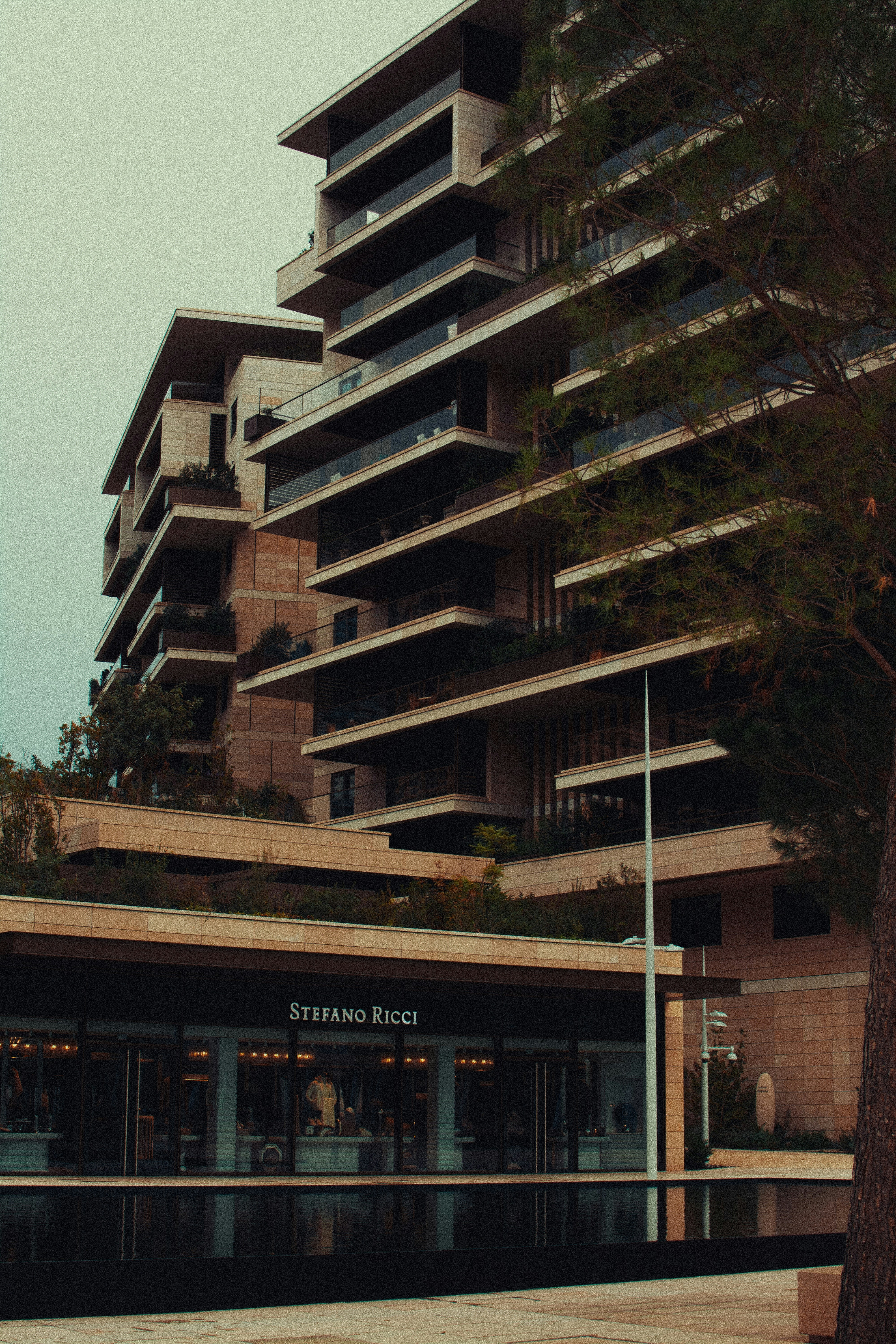 A modern residential building with layered balconies and soft natural lighting, blending architecture and greenery.