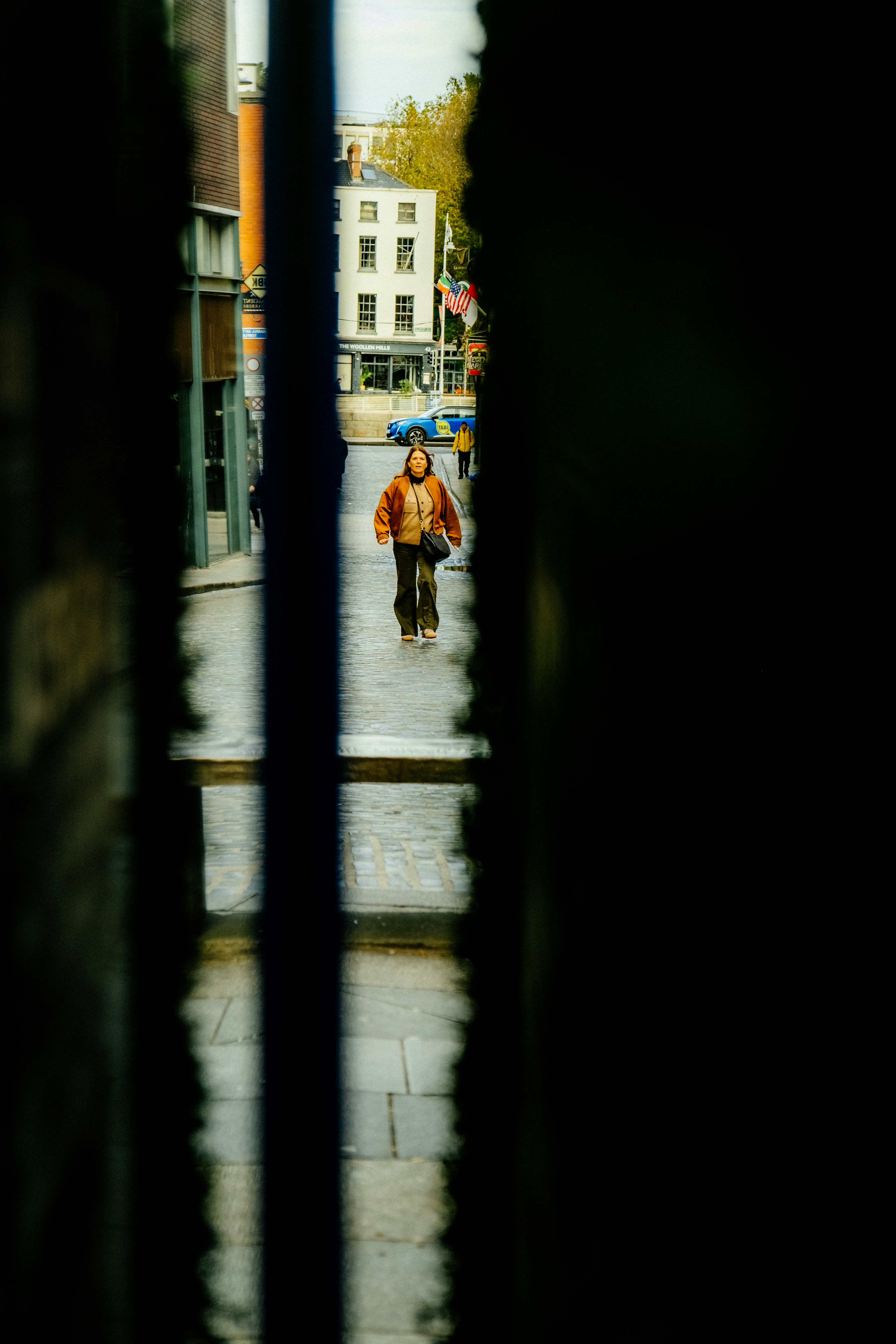 Through the Narrow Gap: A Street Scene Framed by Iron Prominence