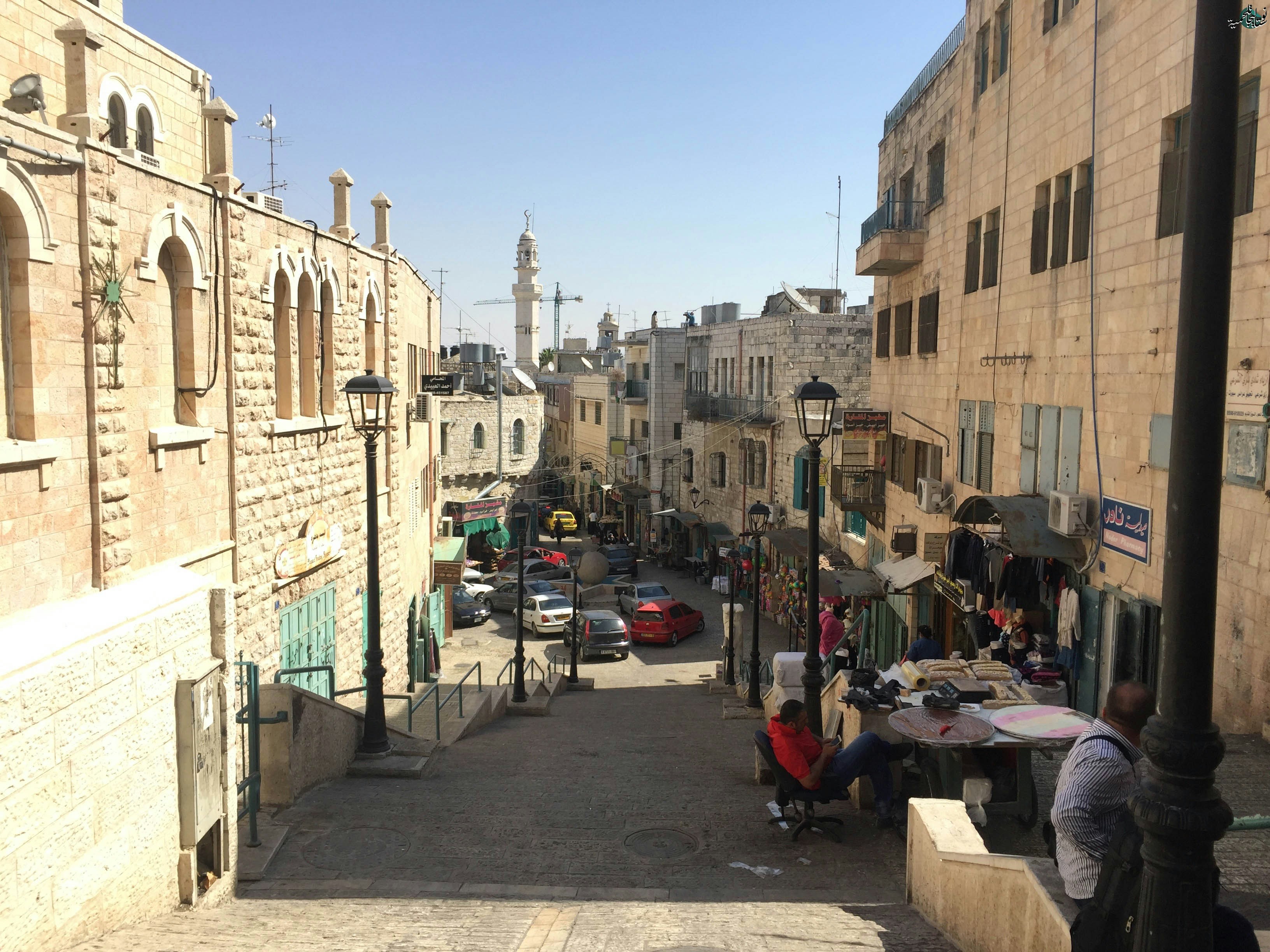 Stone-arched Street Vista: Market Life and Clock Tower in the Distance