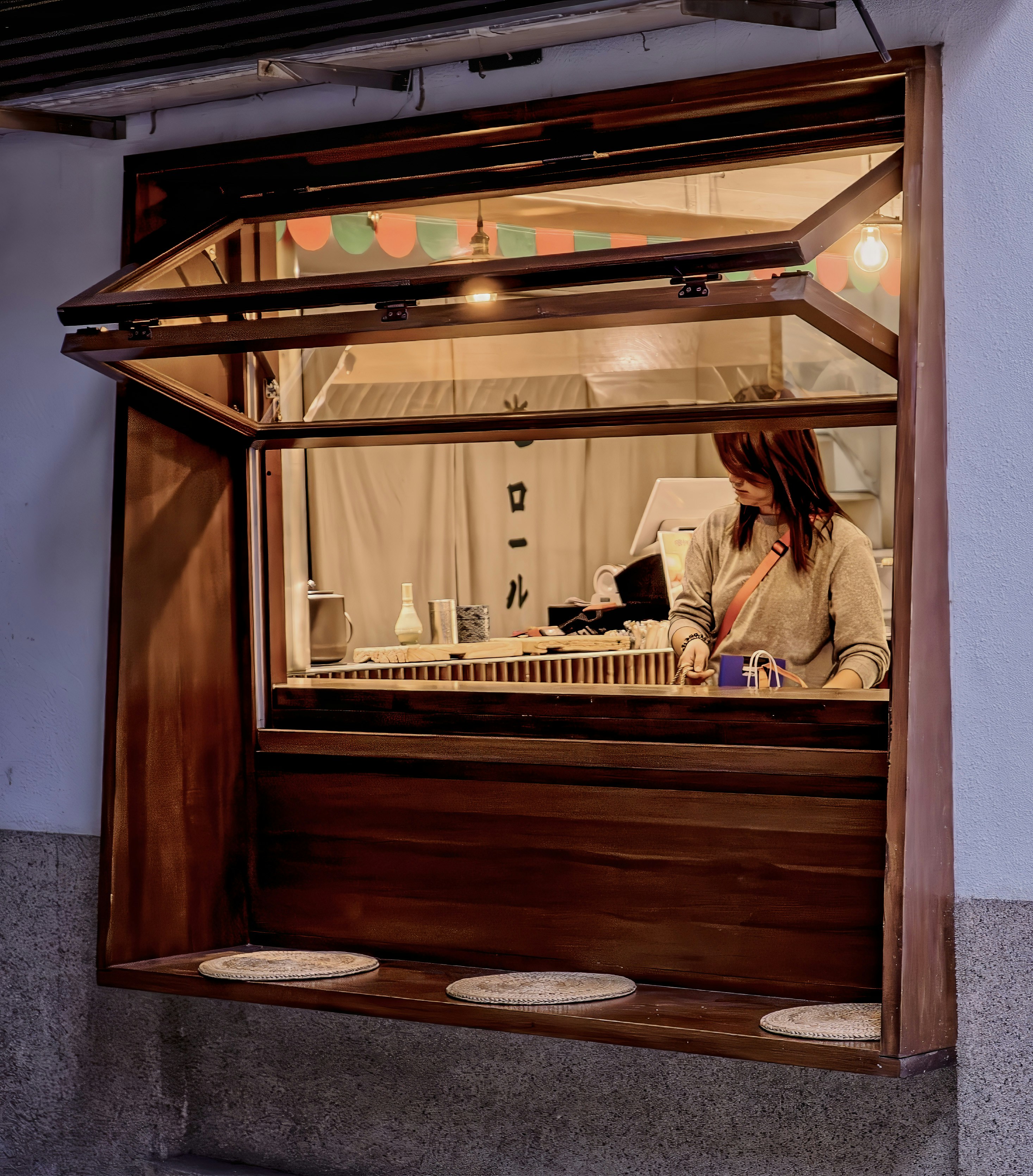 Woman working at a small wooden counter window.