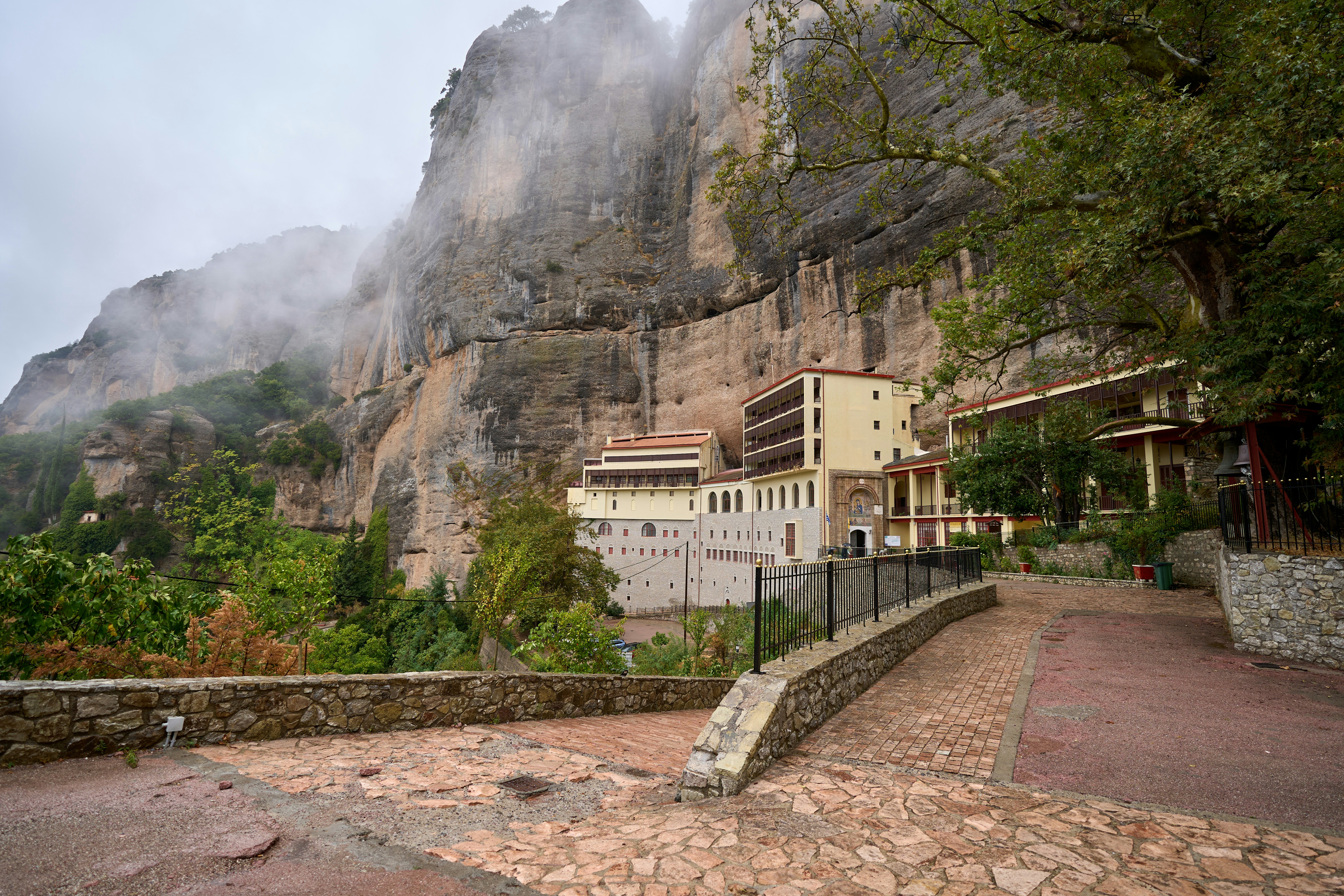 Monastery built into a steep, rocky mountainside with fog. photo – Free ...