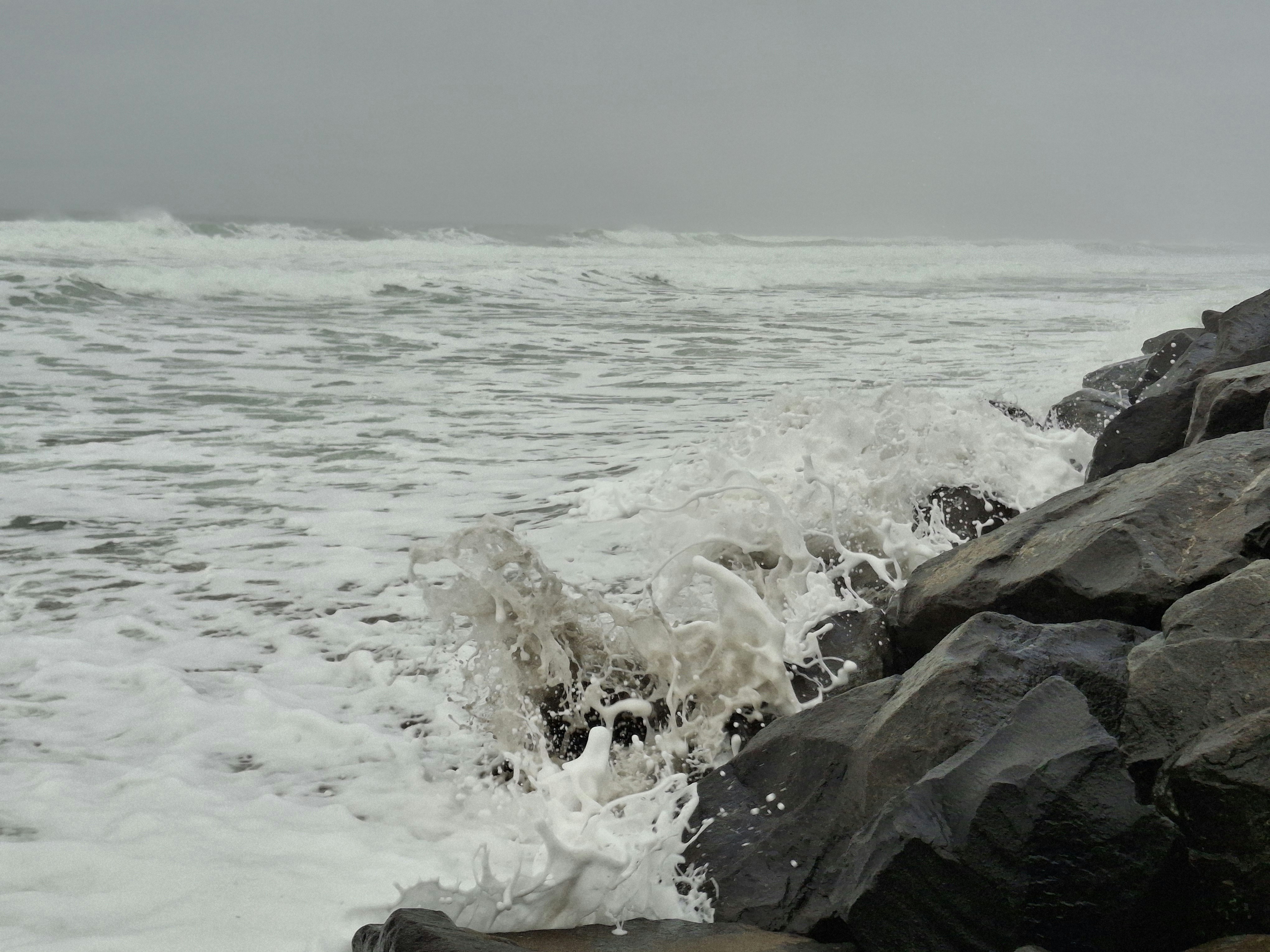 Waves crashing against rocks on a foggy day.