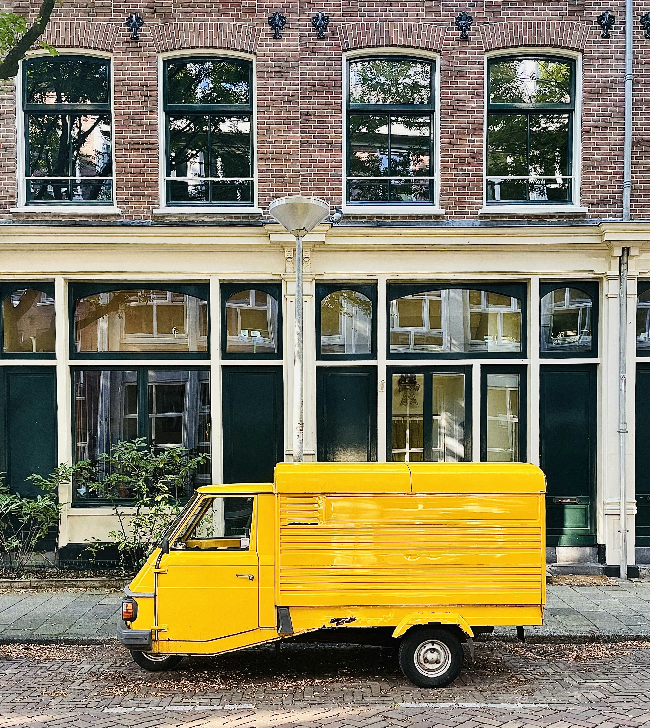 Yellow Delivery: A Bright Van Resting Before a Classic Brick Facade
