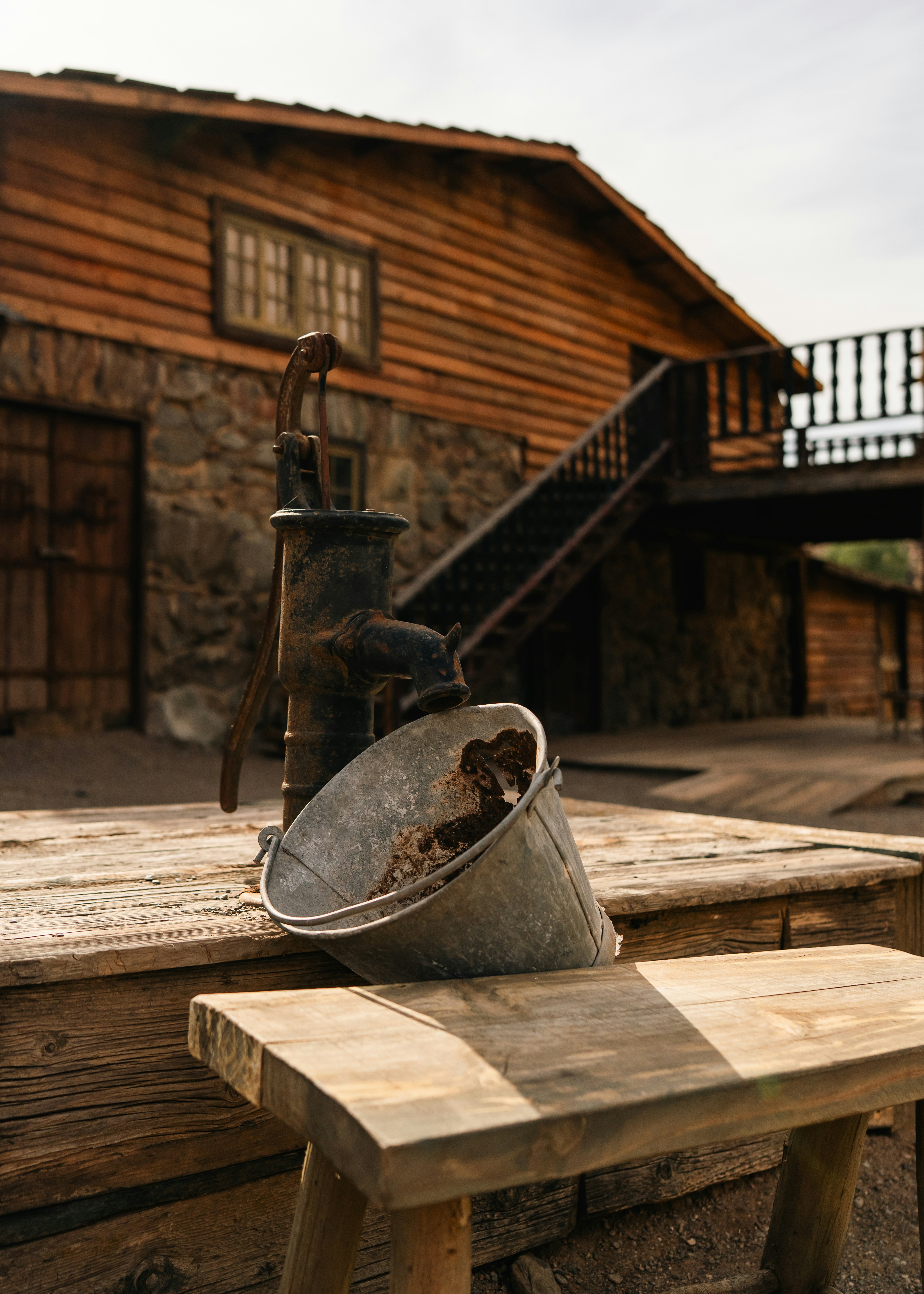 Rustic Water Pump and Bucket on a Weathered Wooden Deck