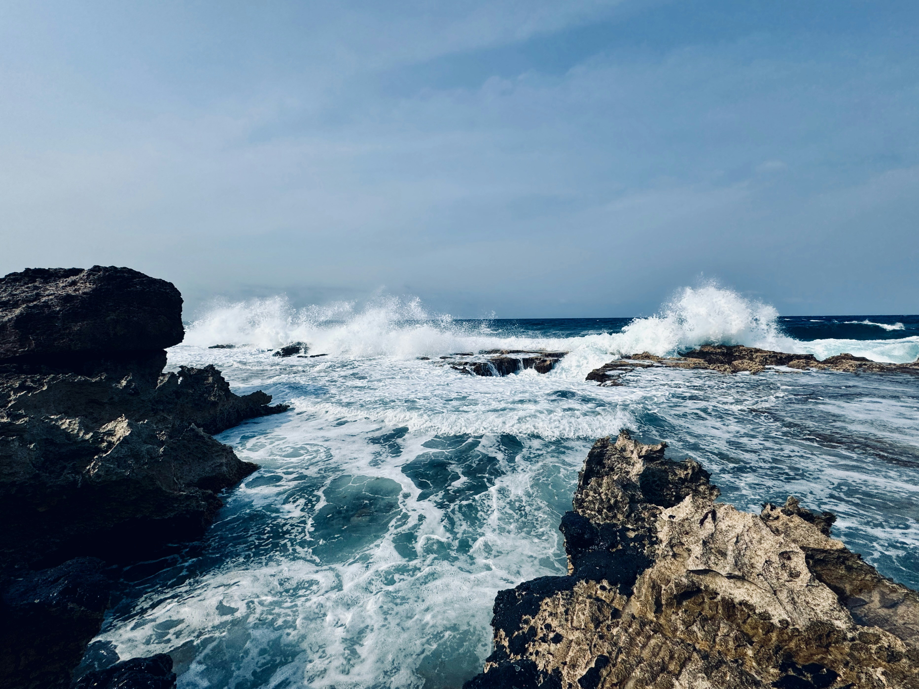 Las olas rompen contra la orilla rocosa bajo un cielo despejado foto ...