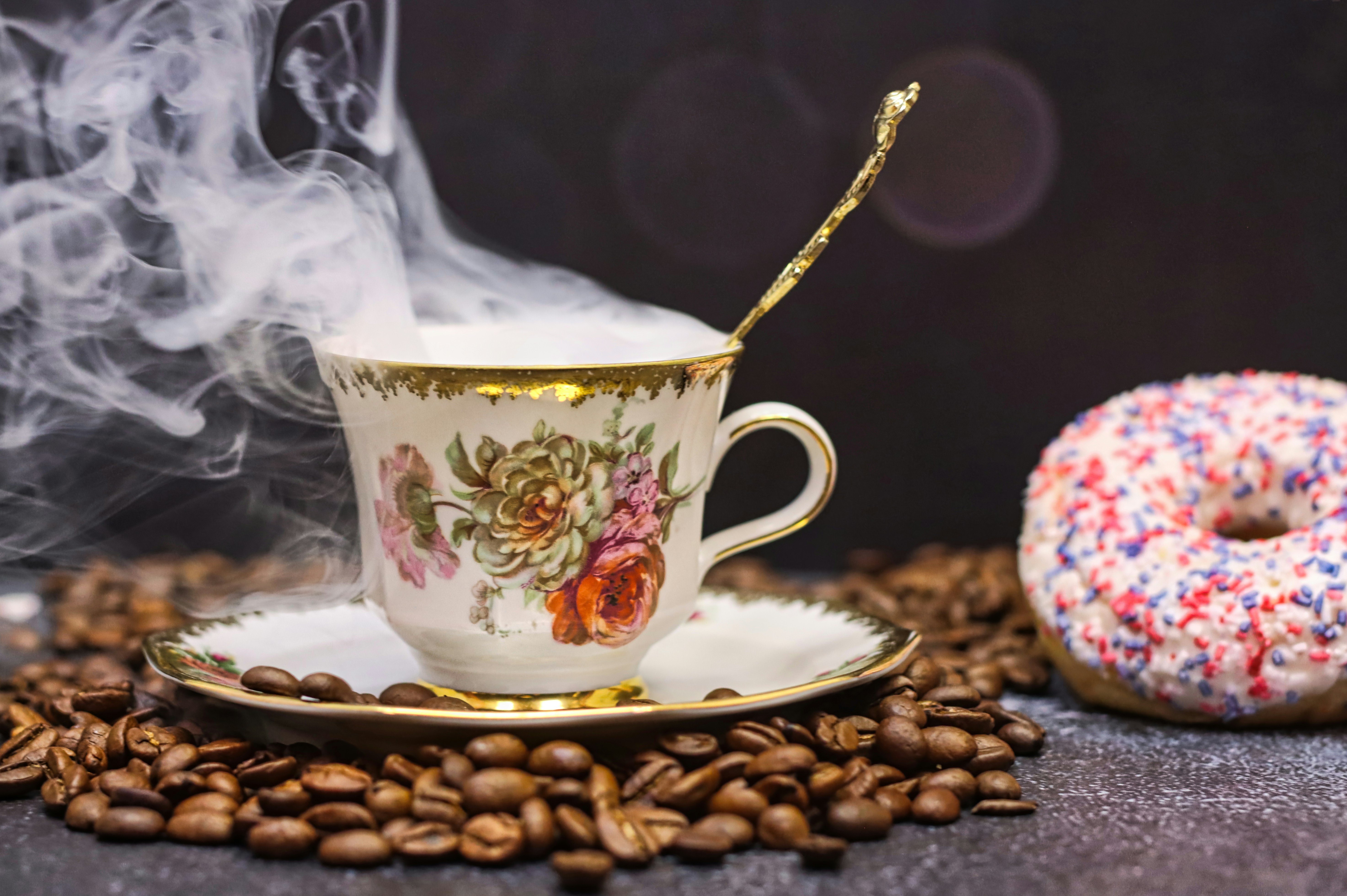 Vintage Tea Cup Amid Coffee Beans and a Sprinkled Donut