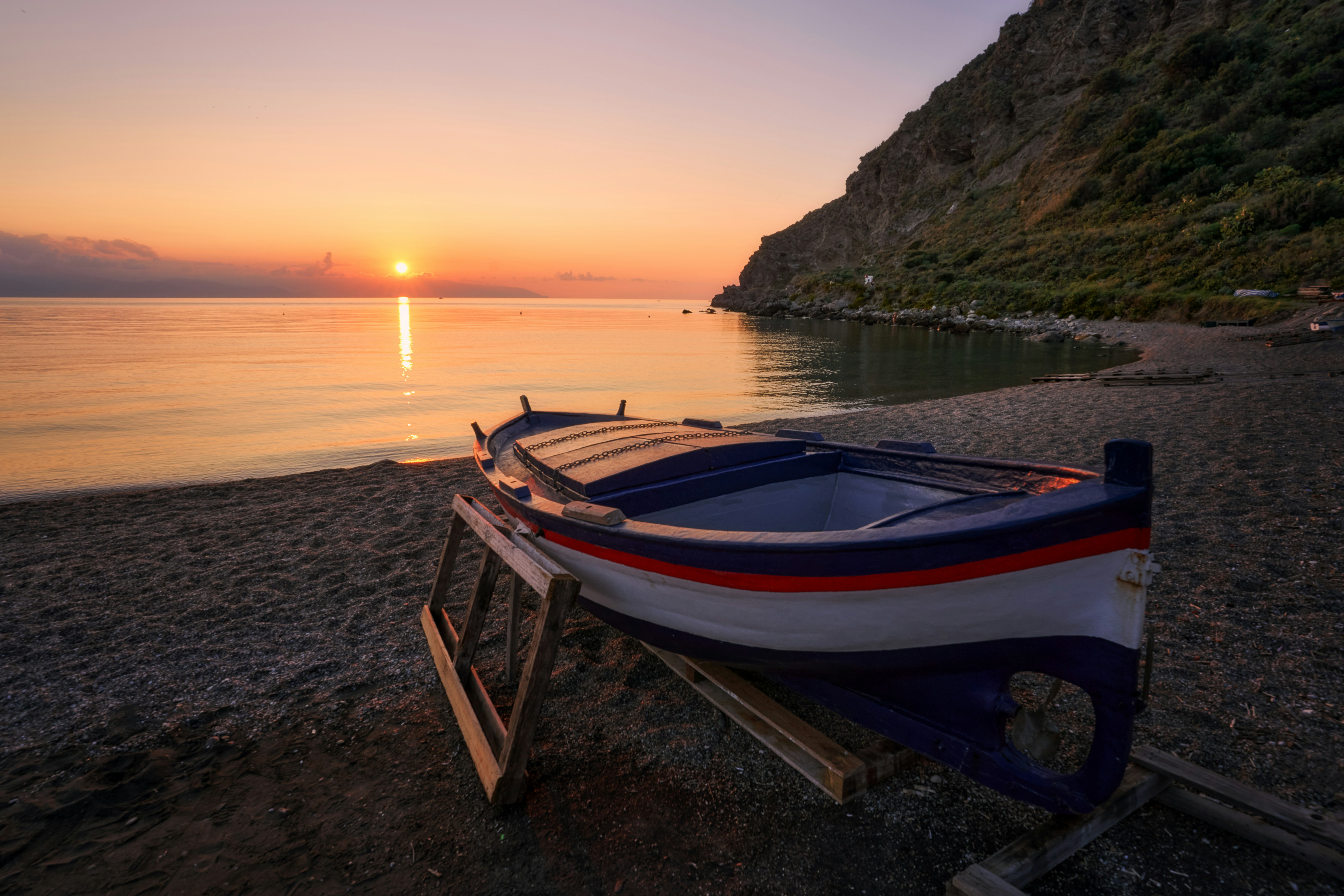 Sunlit Bow: Boat on a Pebbled Shore at Dusk