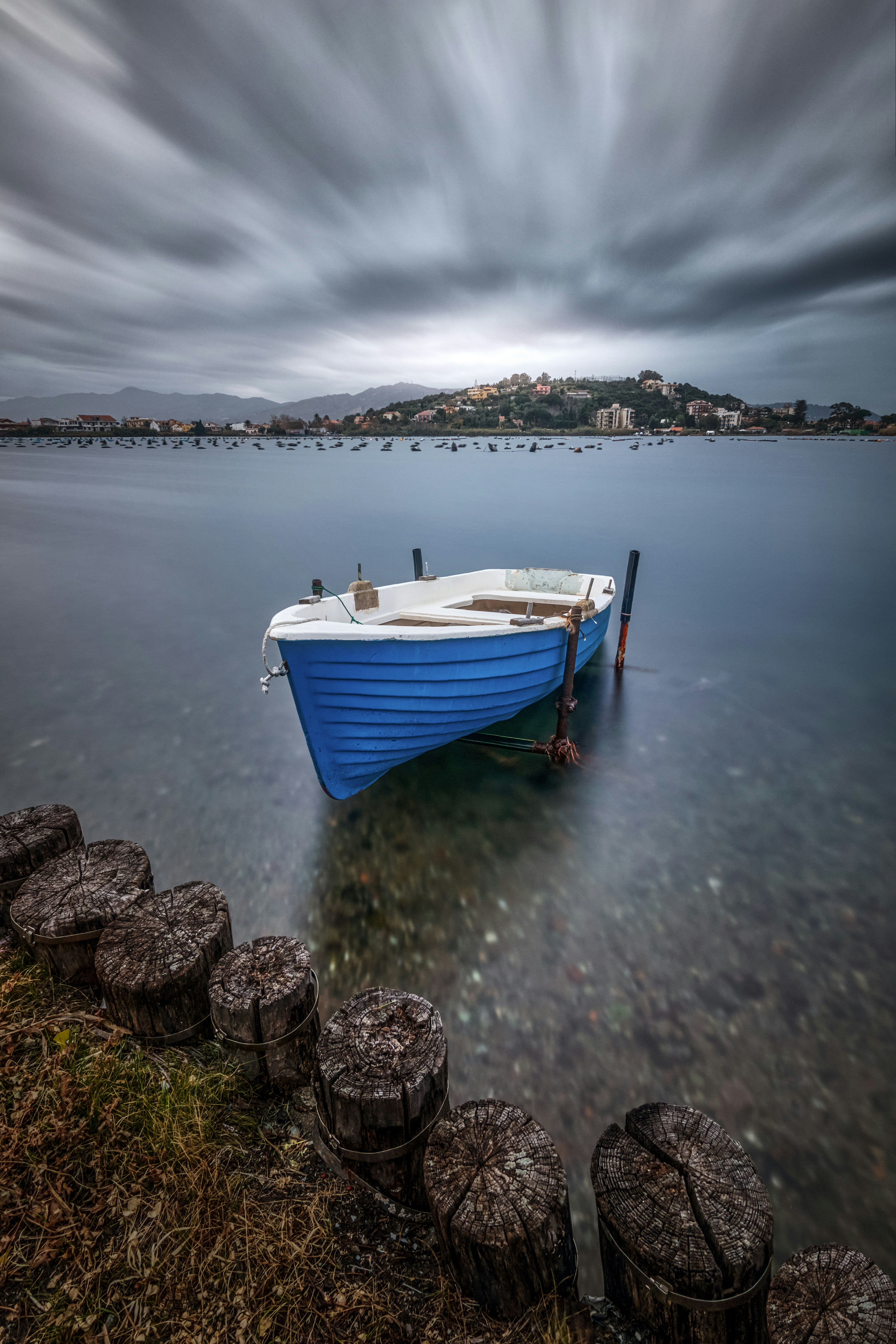 Blue Boat in Calm Lagoon Under Dramatic Sky