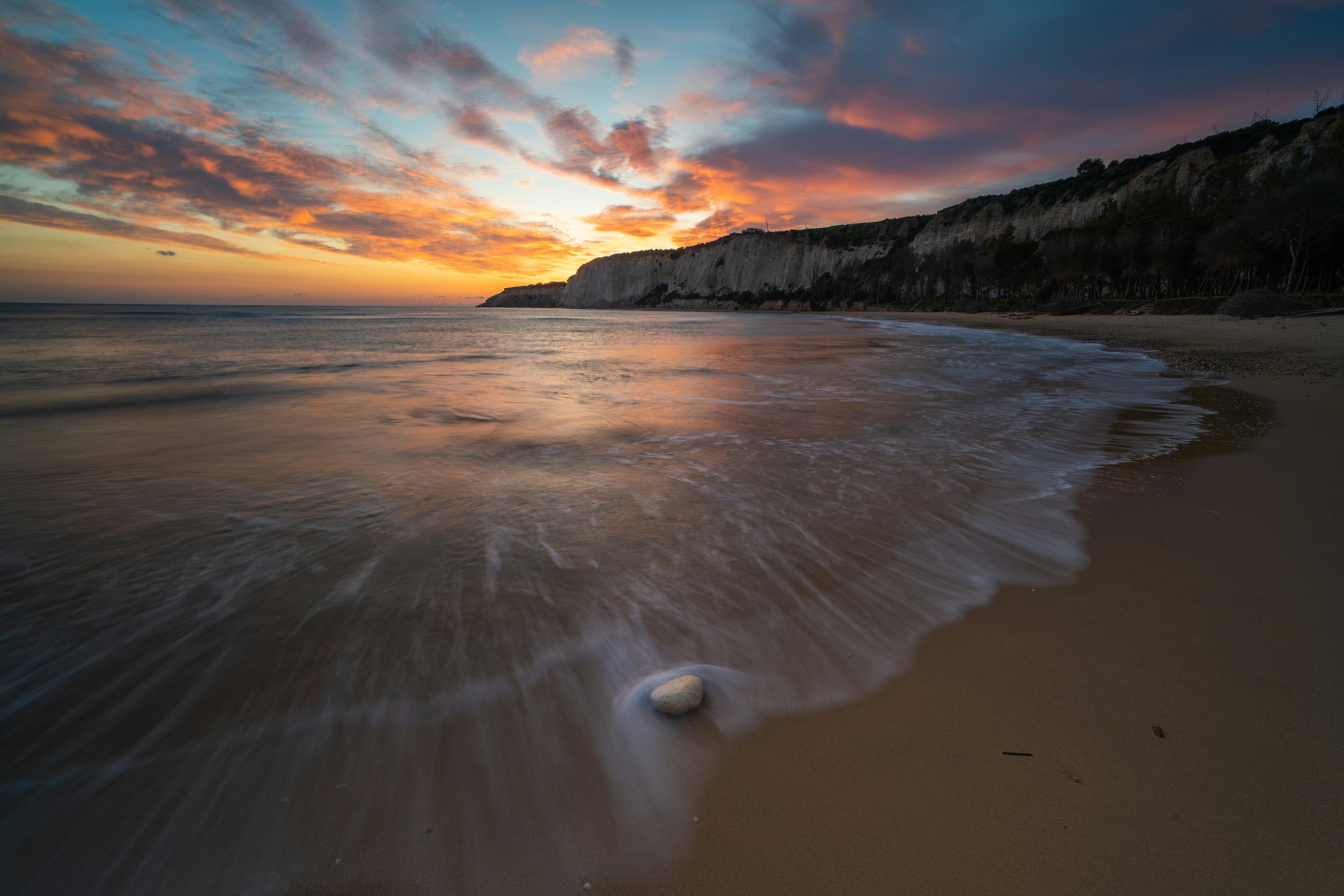 Sunset Tide: Pebble in the Foreground as Dusk Washes the Shore