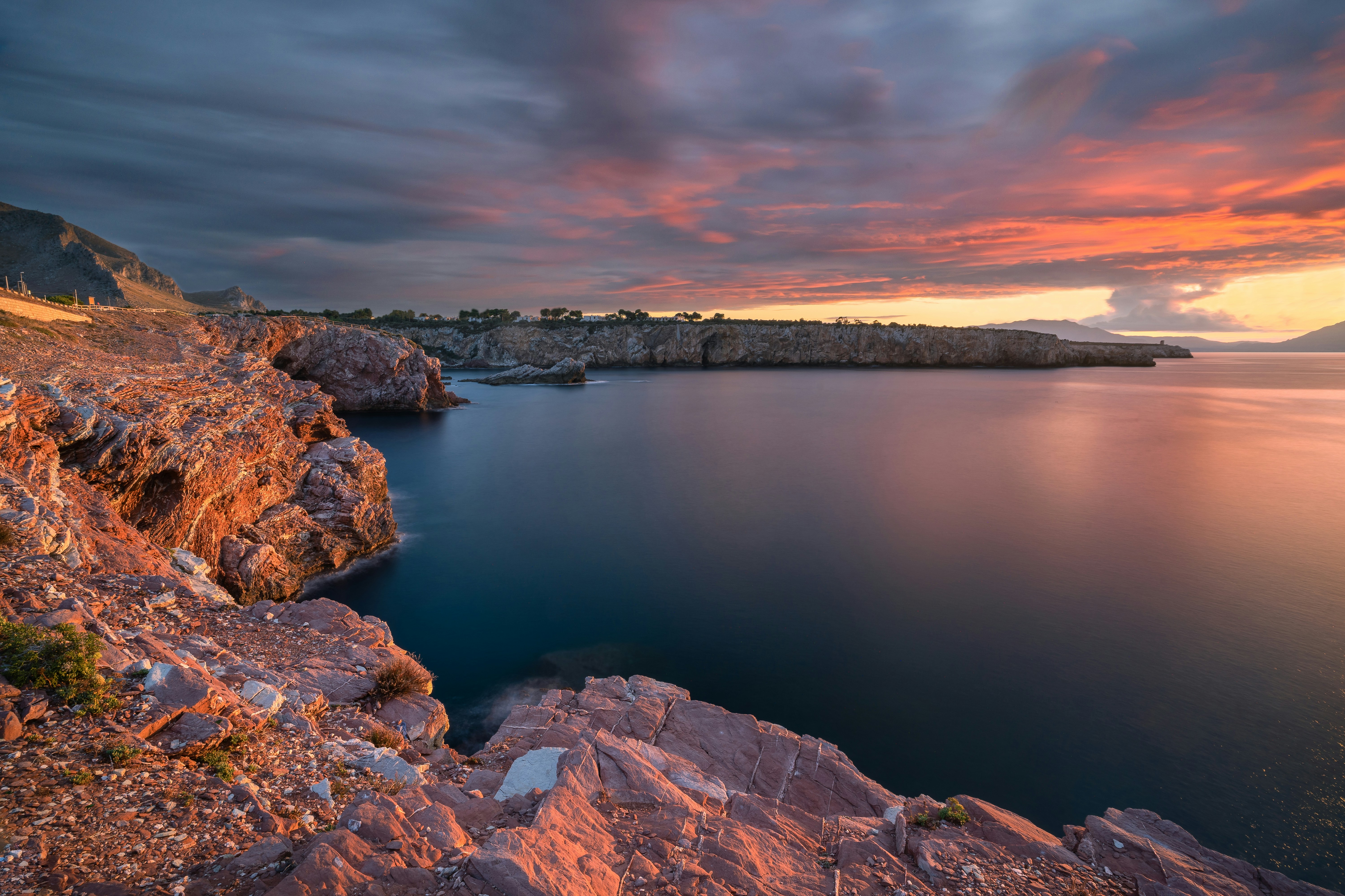 Sunset Over Rugged Cliffs: Quiet Sea Beneath a Fiery Sky