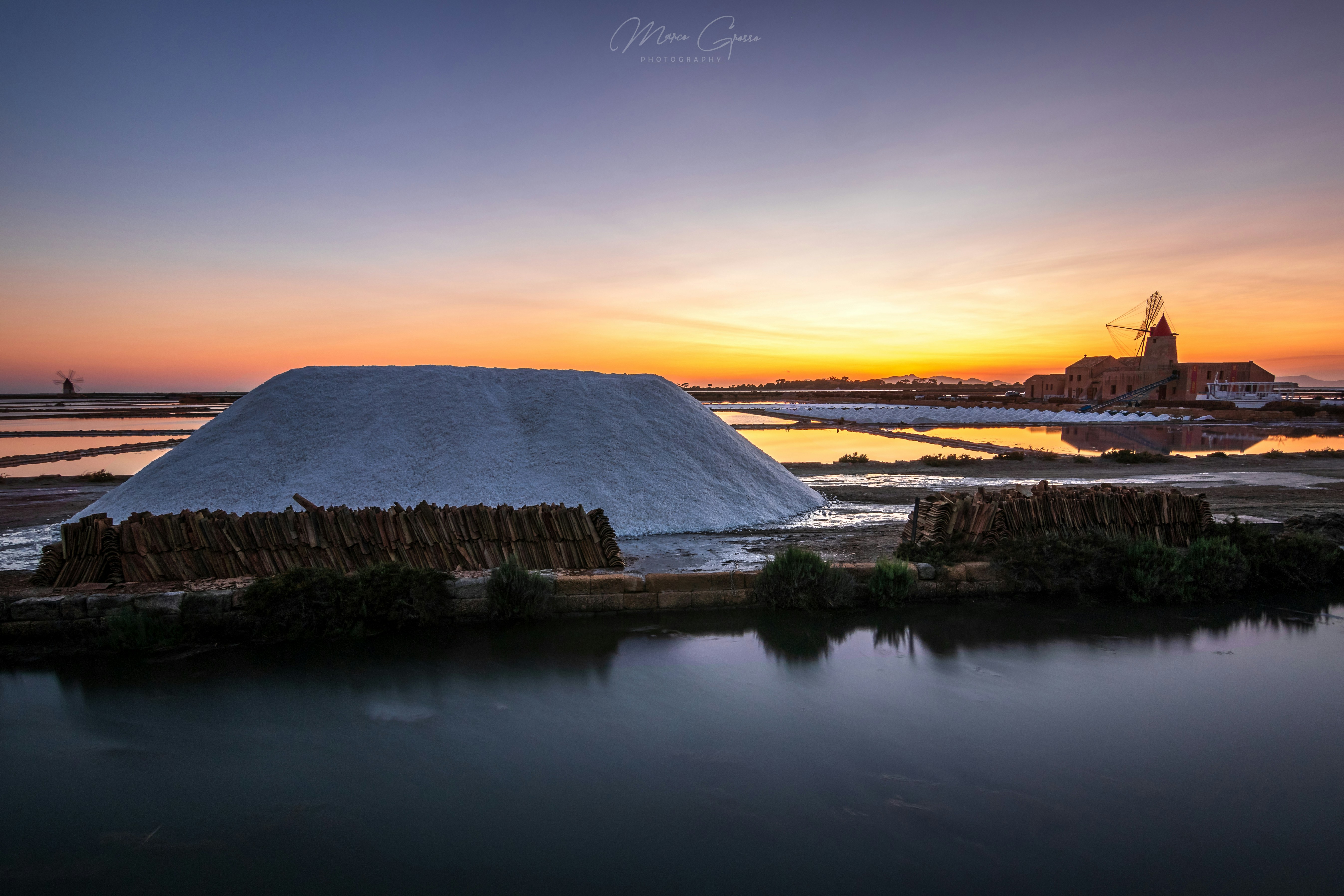Salt piles and windmill at sunset with calm water. photo – Free Sunset ...