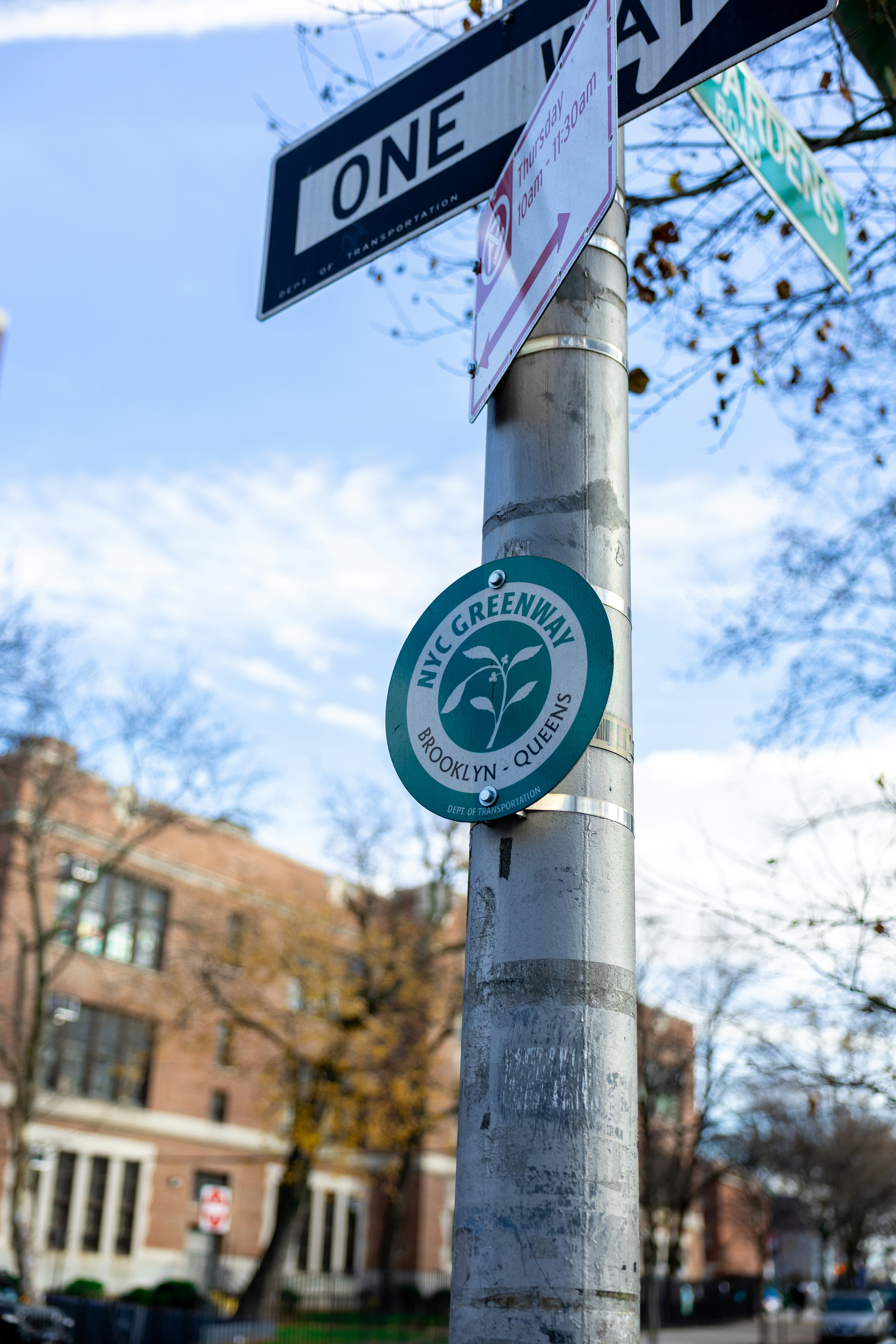 Urban Signpost Portrait: NYC Greenway badge on a weathered pole