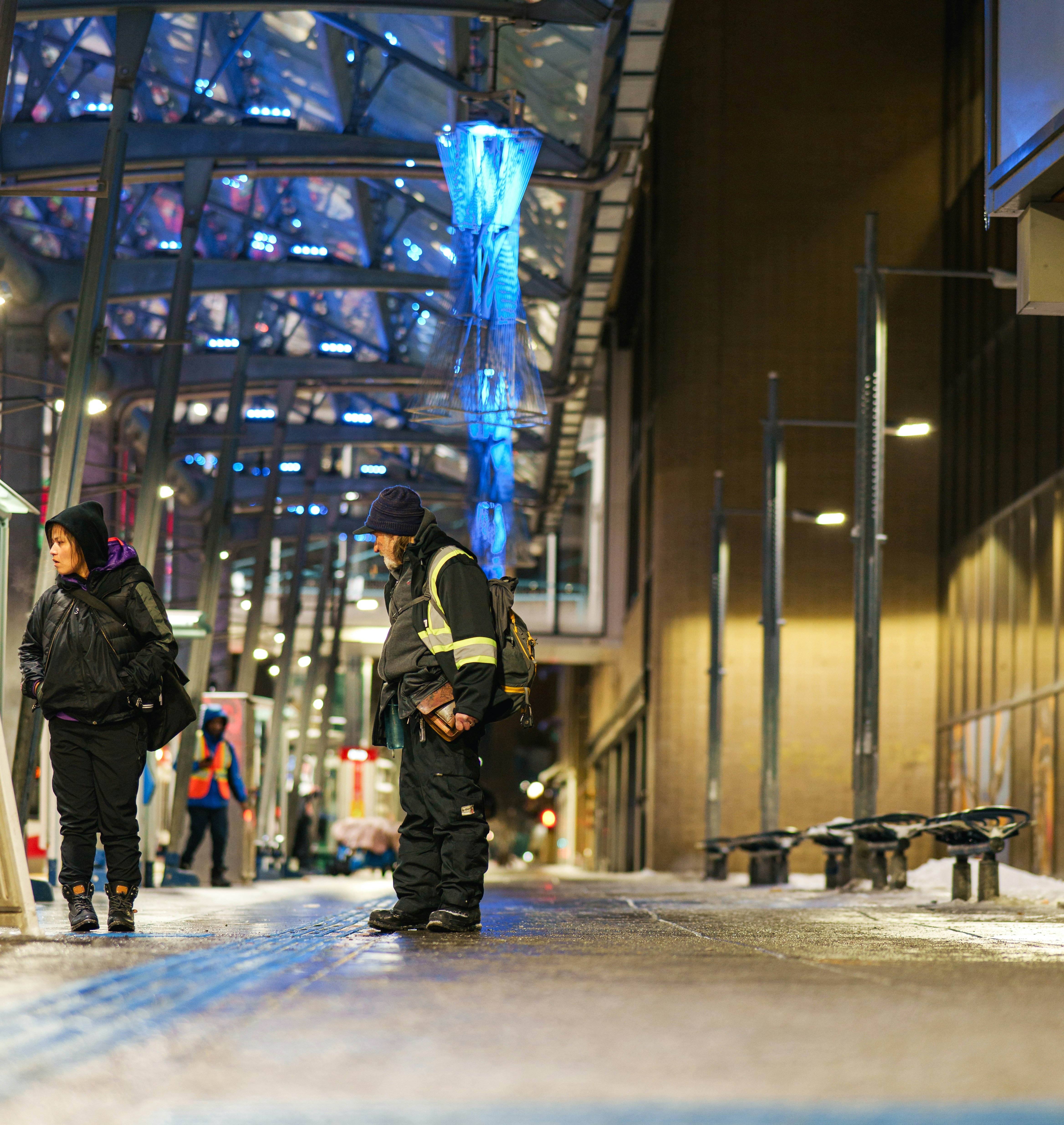 Nighttime in the Glass Tunnel: Workers and Warm Light Amid Snow and Steel