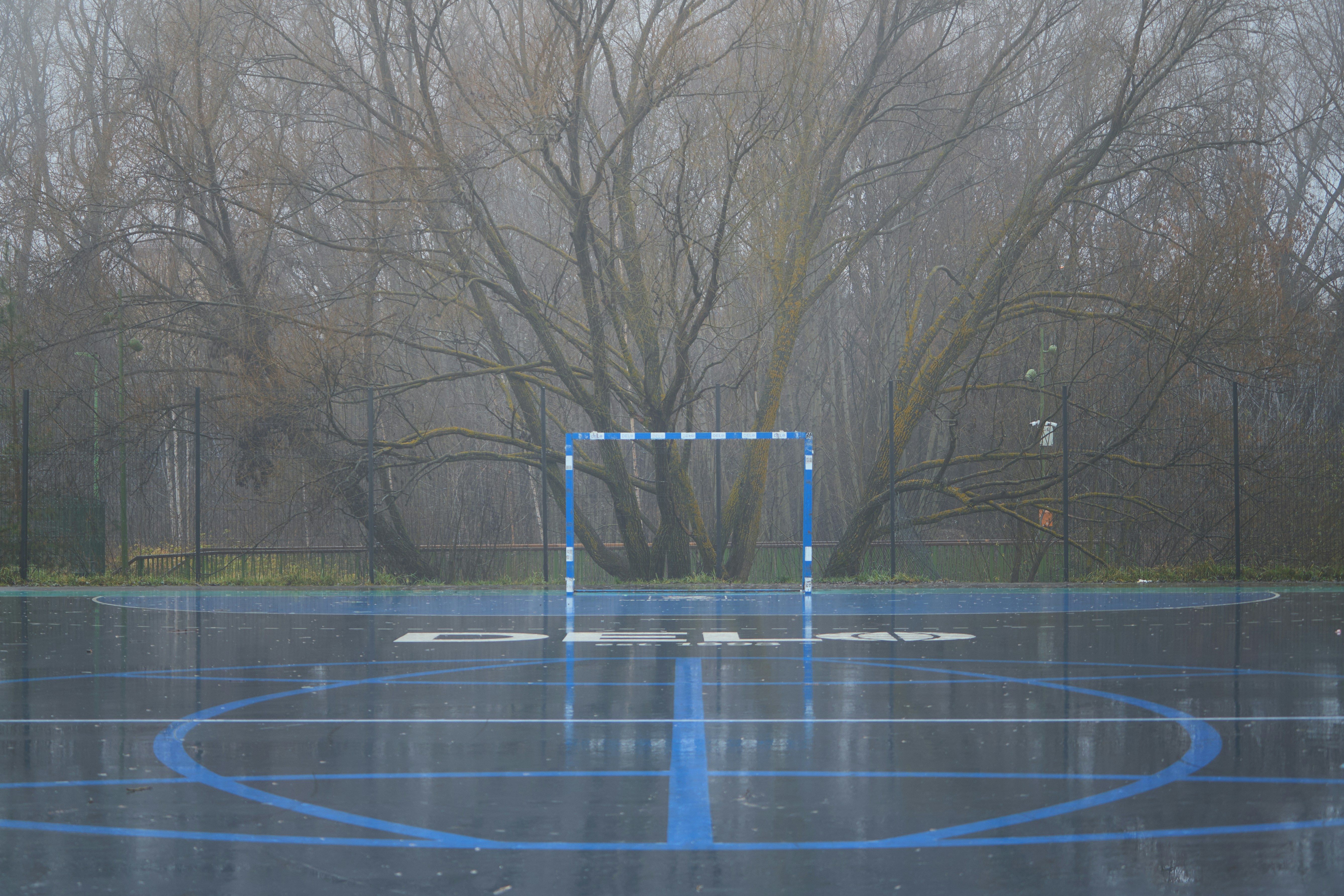 Rainy Field Goal: Blue Circle Markers on a Slick Court