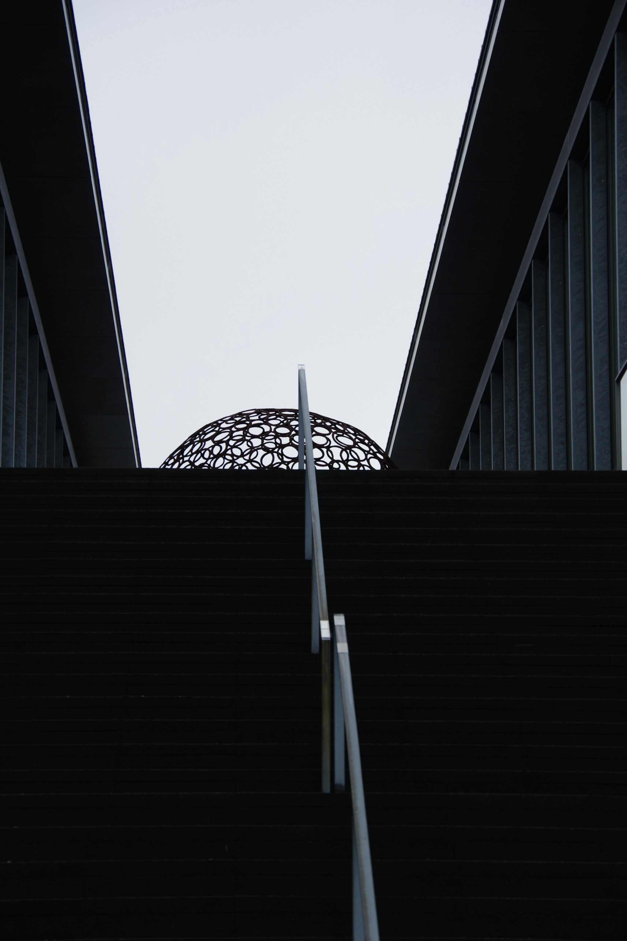 Symmetry at the Summit: Circular Trellis Piercing the Sky Above Stairs