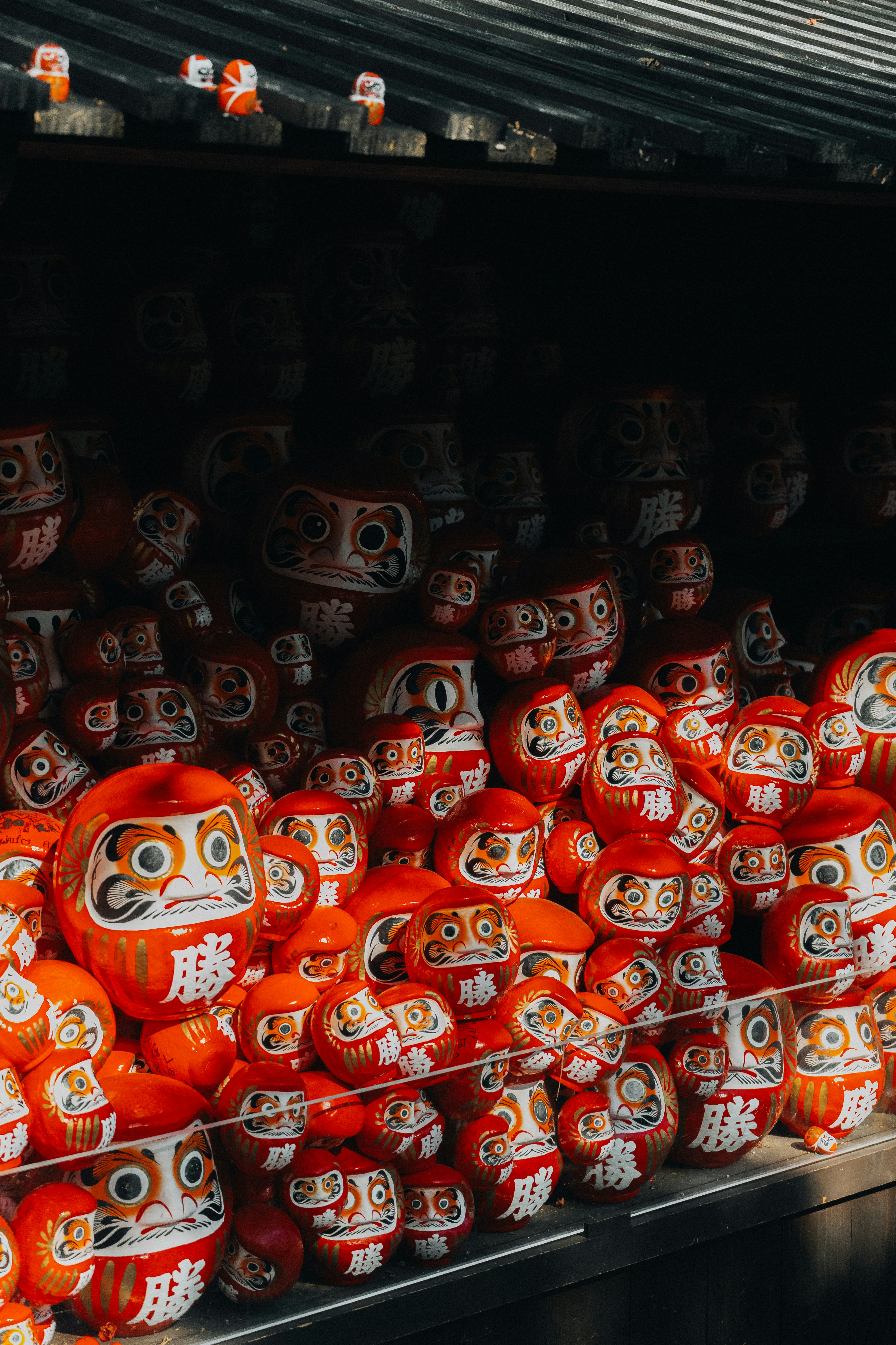 A collection of small figurines photographed at Katsuo-ji Temple in Osaka, Japan. The statues are captured from multiple angles, showcasing their detailed craftsmanship, traditional design, and placement within the temple grounds.
