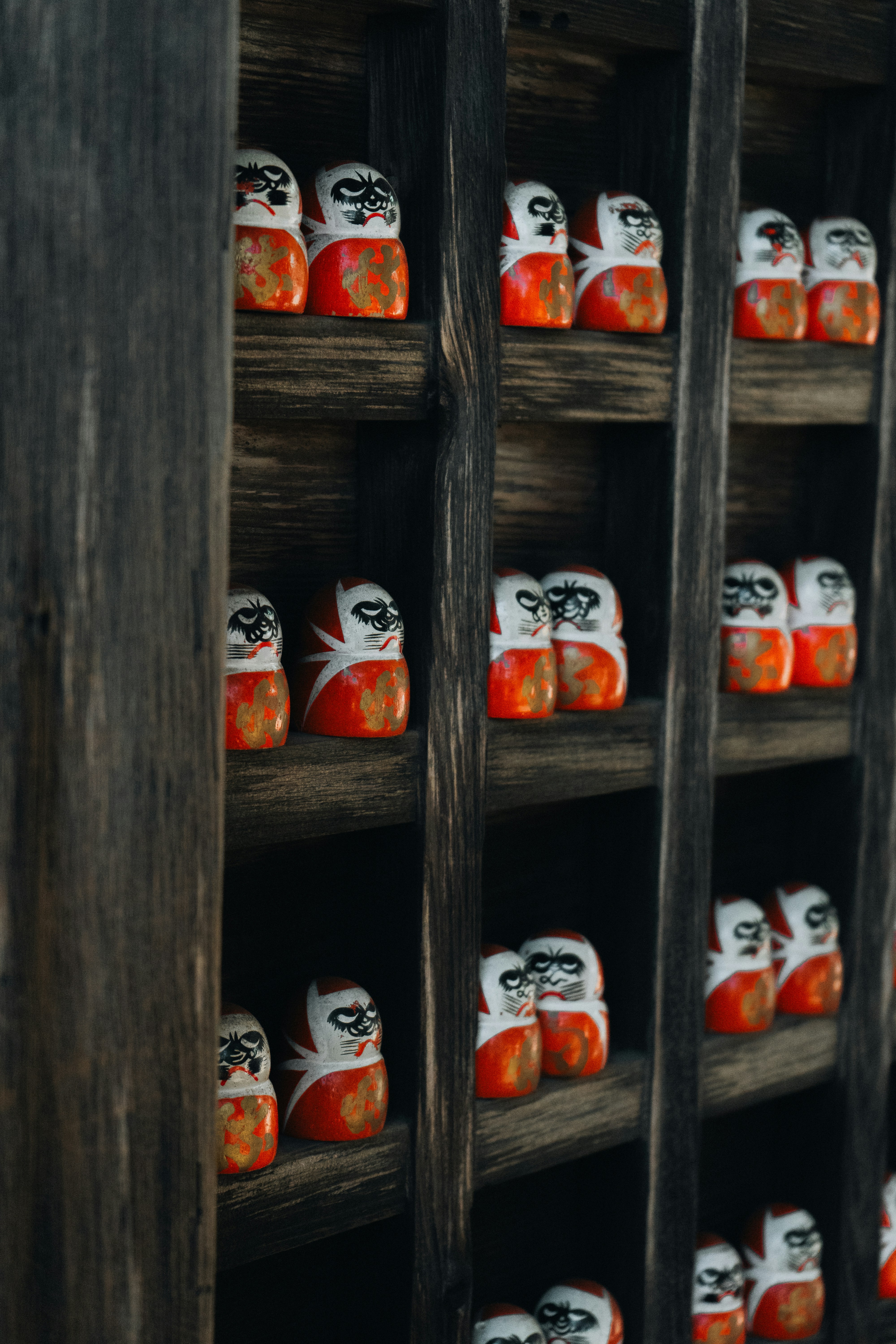 Rows of Daruma Dolls Framing a Weathered Wood Grid