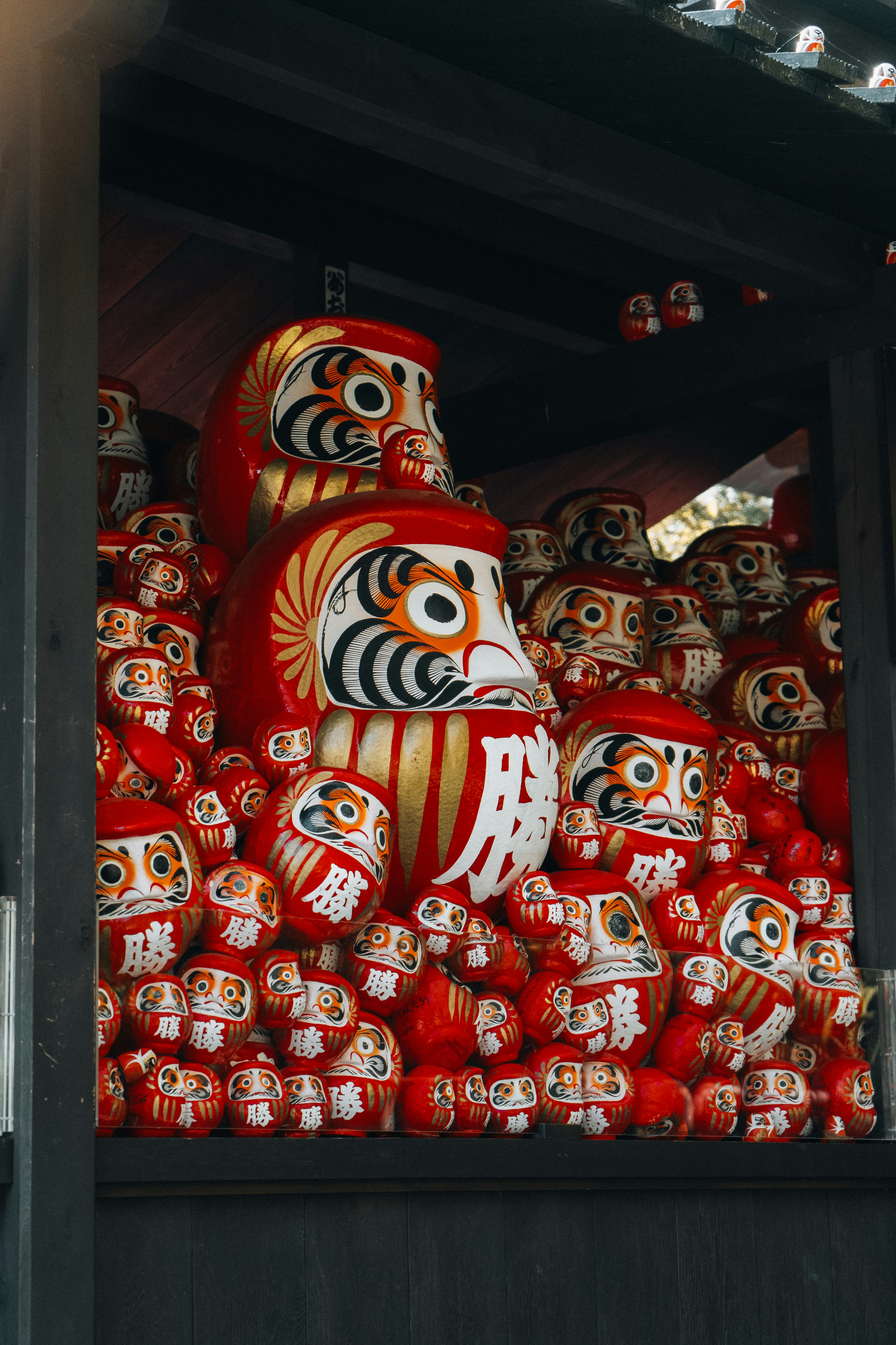 A collection of small figurines photographed at Katsuo-ji Temple in Osaka, Japan. The statues are captured from multiple angles, showcasing their detailed craftsmanship, traditional design, and placement within the temple grounds.