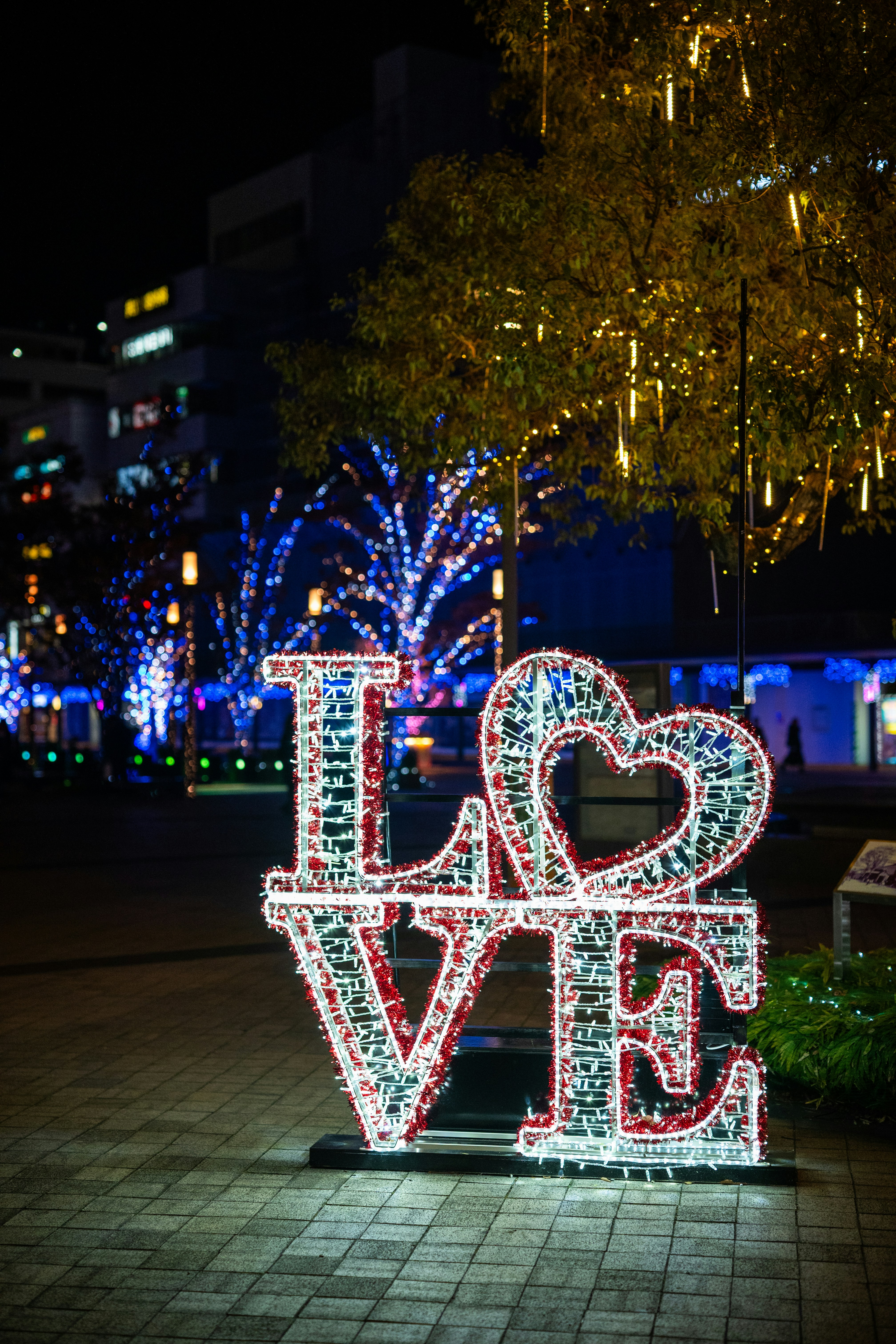 Glowing LOVE sculpture alight in a night-lit urban plaza